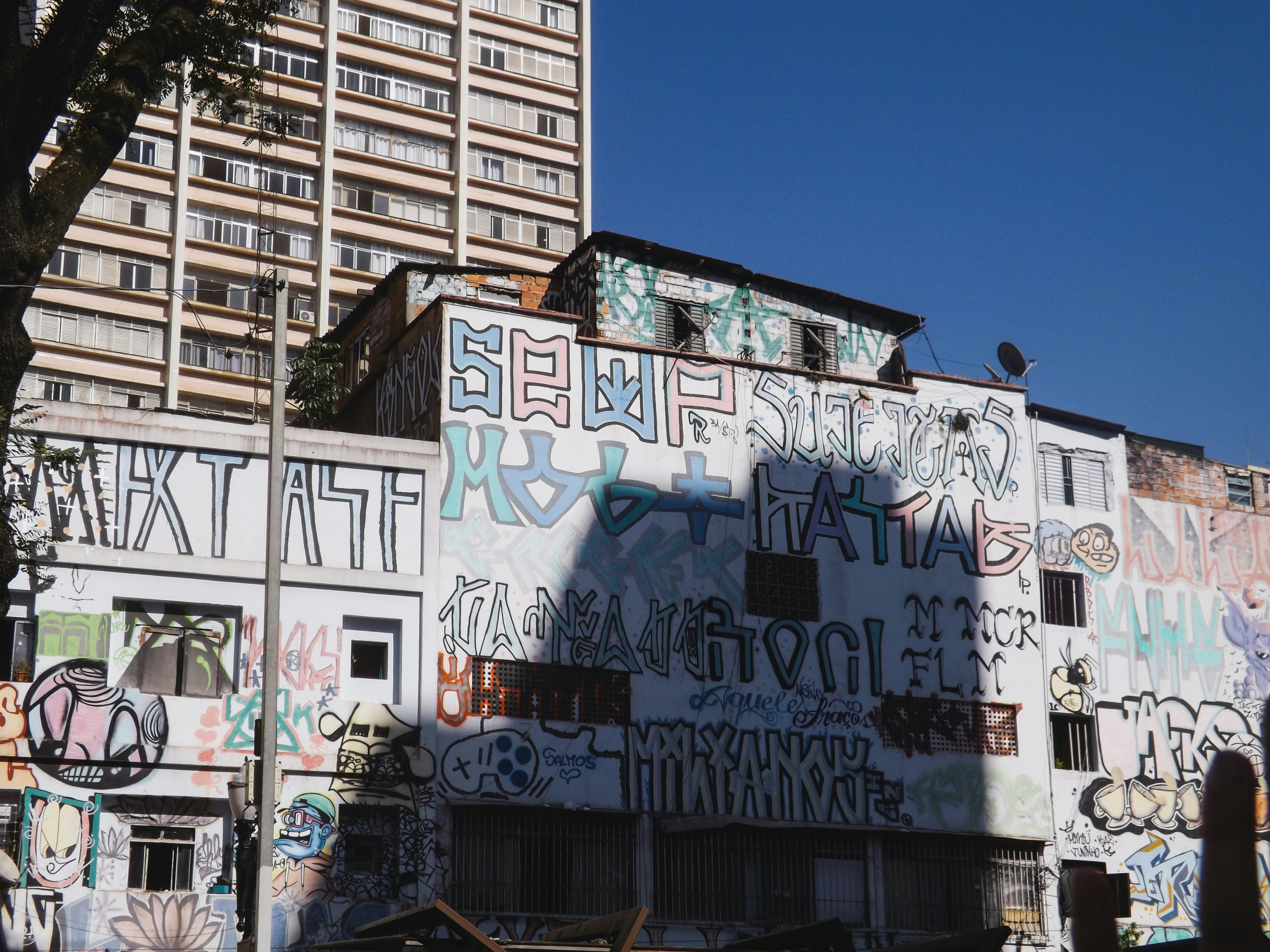 Graffiti covers a building against a sunny blue sky.