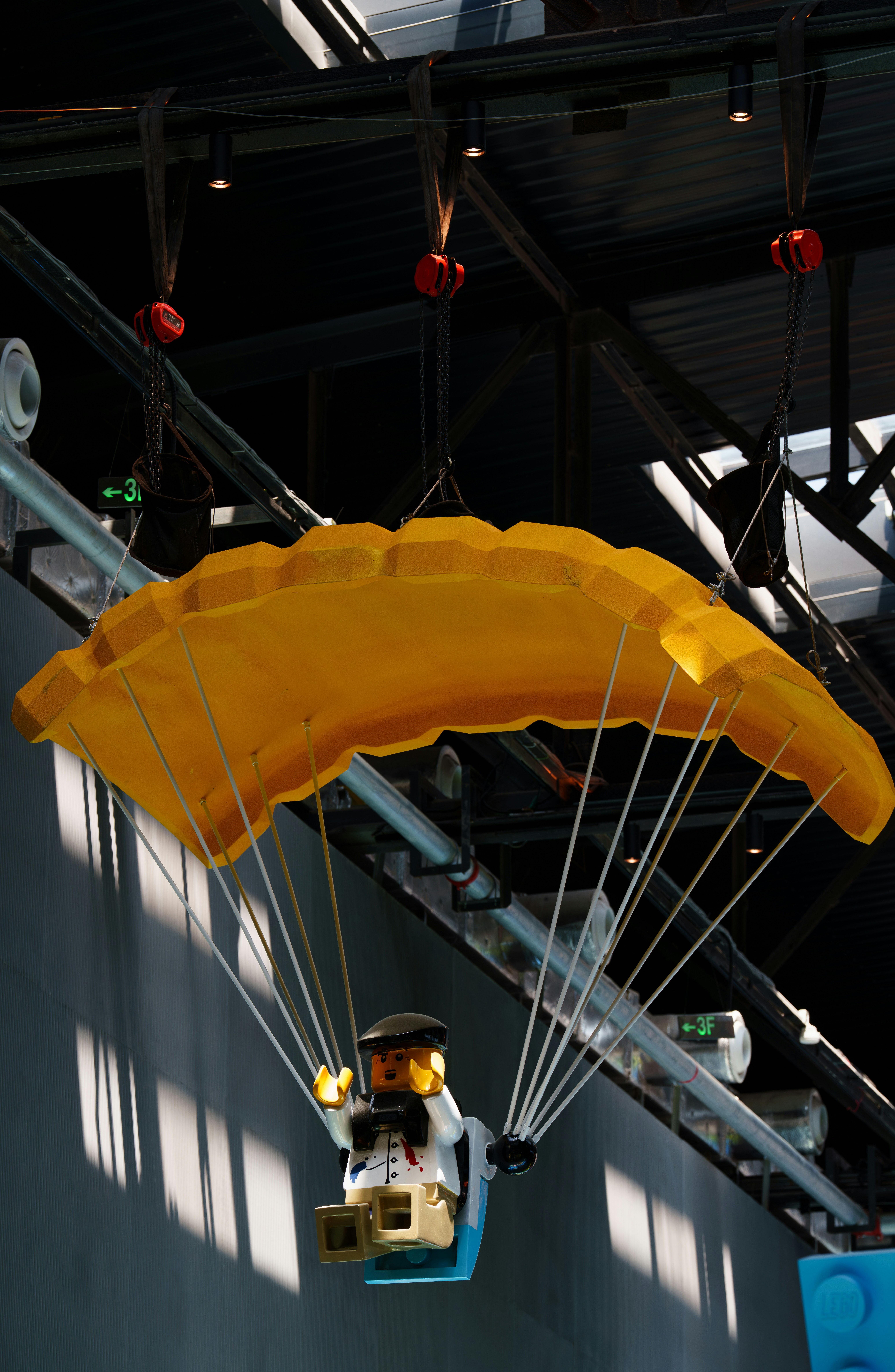 A lego figure is parachuting from the ceiling.