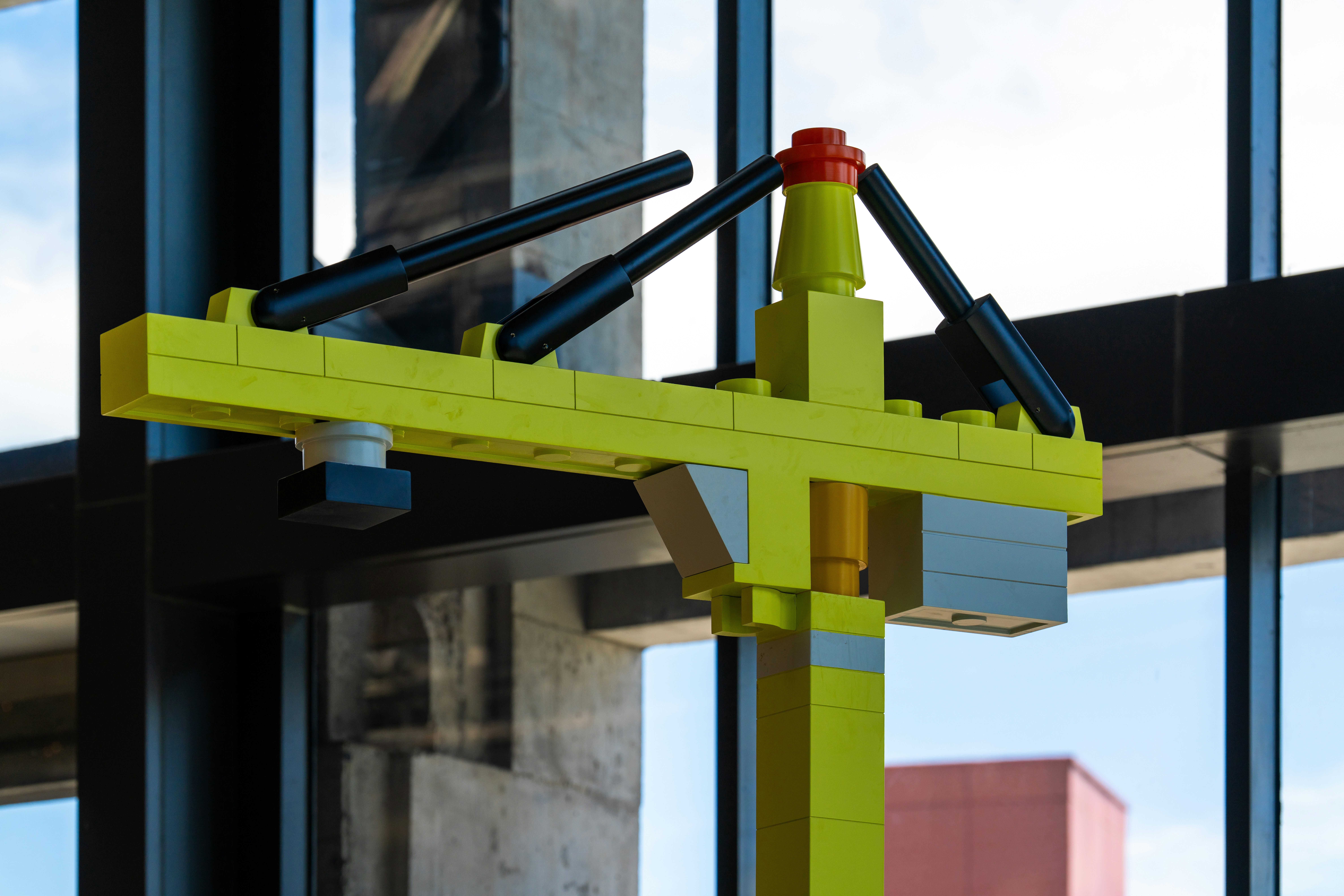 Neon LEGO Crane Suspended in a Glass Atrium