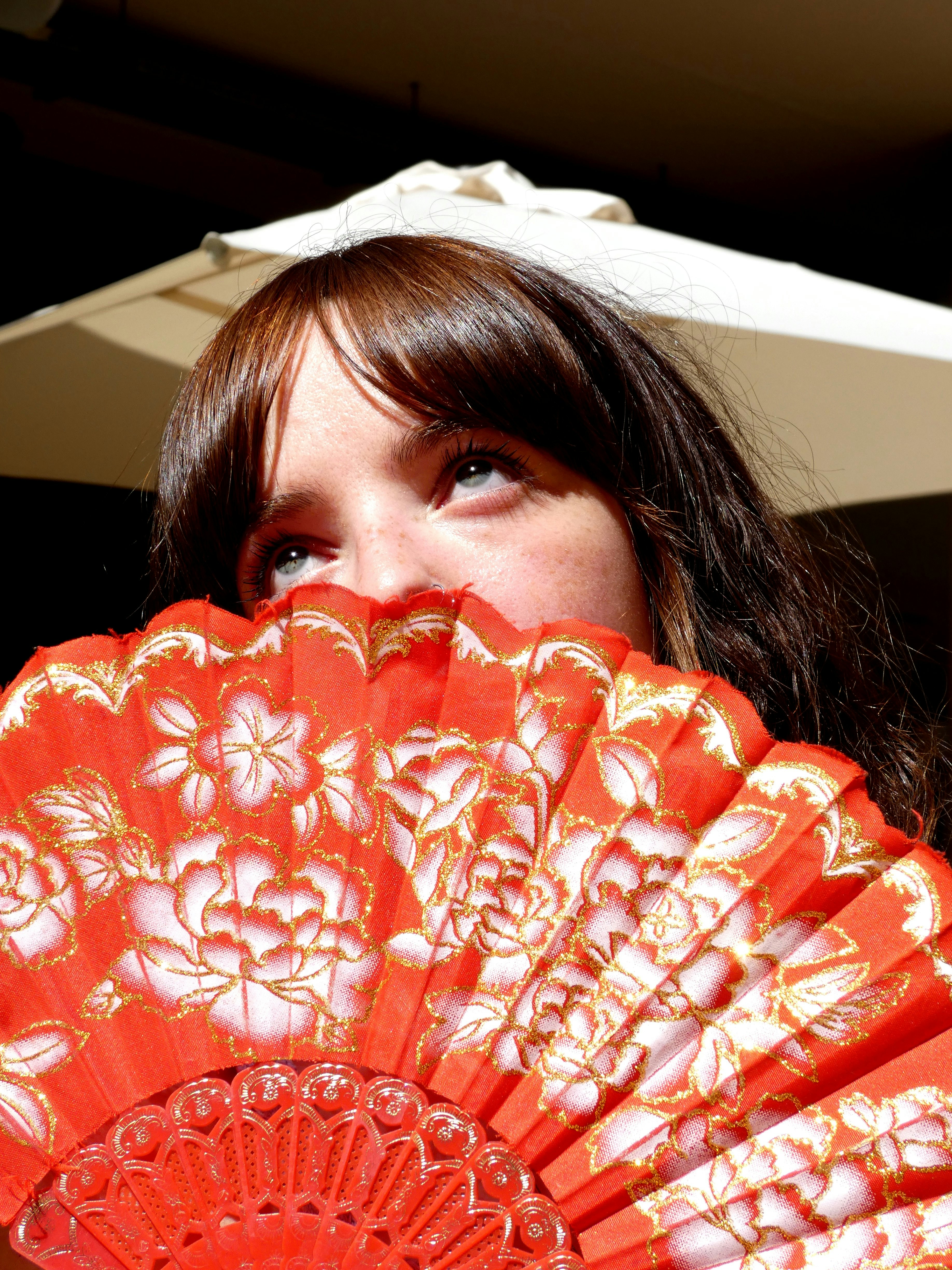 Scarlet Veil: A Glimpse of Eyes Above a Red Fan