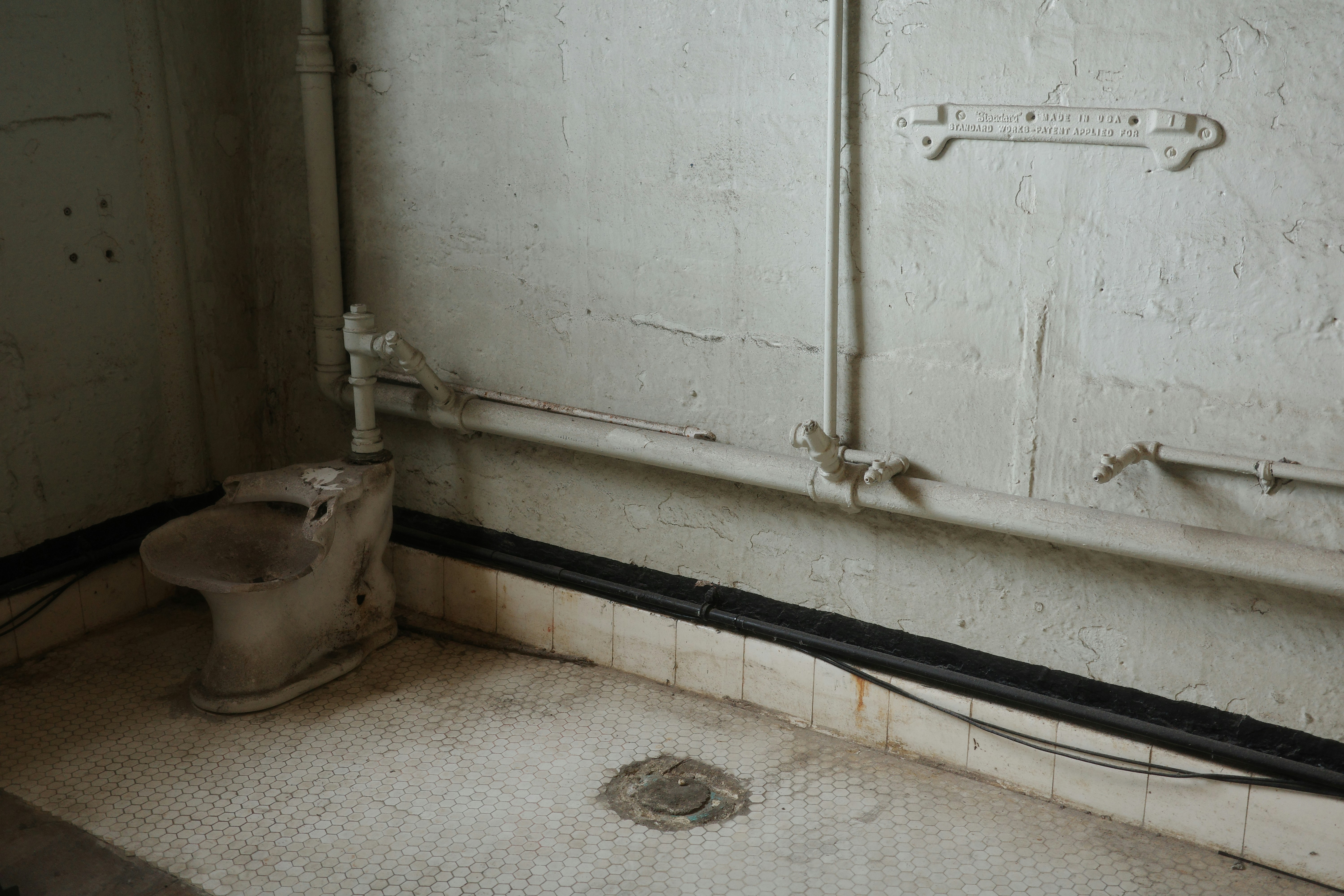 An old, white toilet in a grungy bathroom.