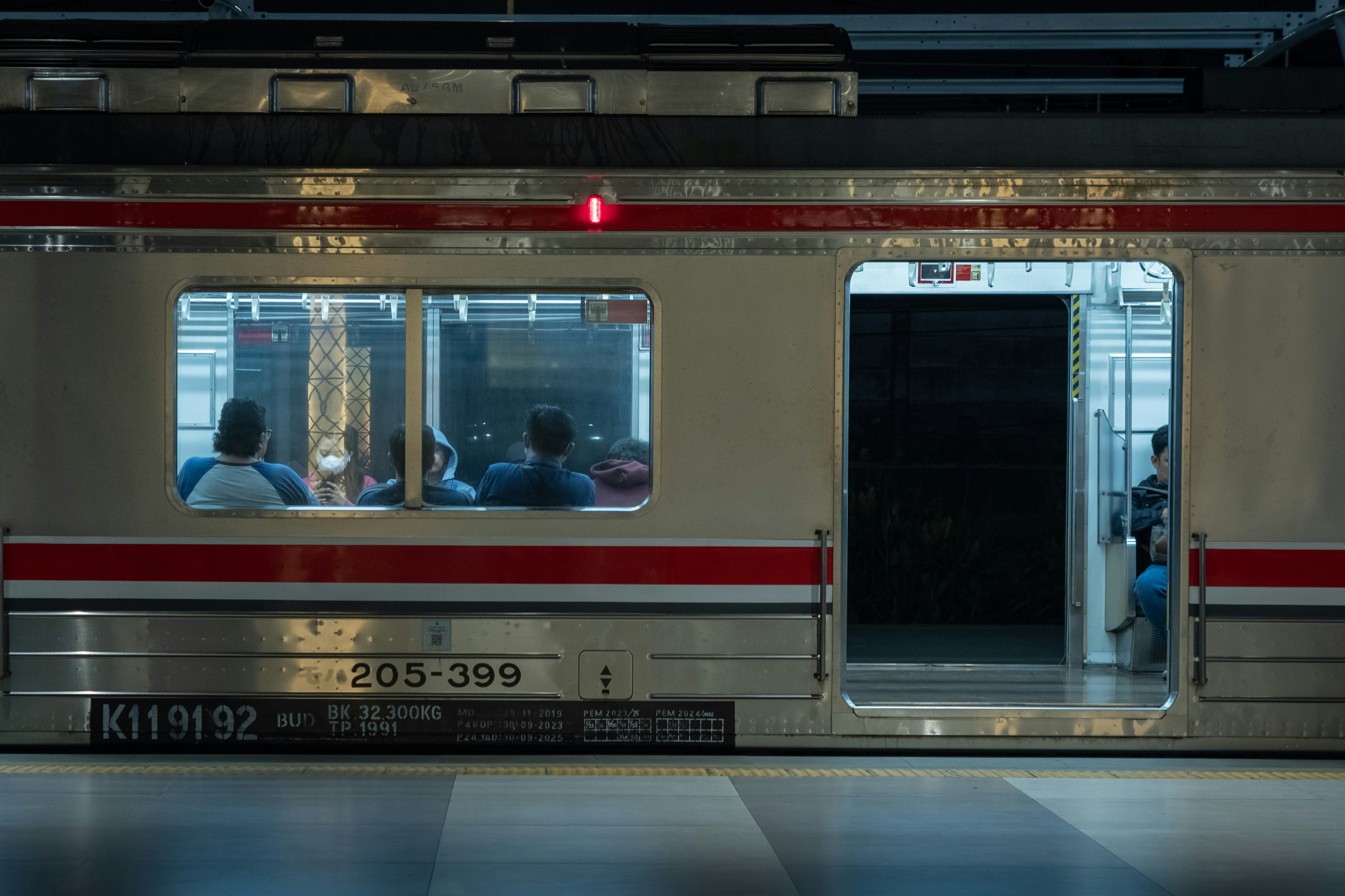 A Train arrive at Tanah Abang Station, Jakarta. | A train car with open door and passengers.