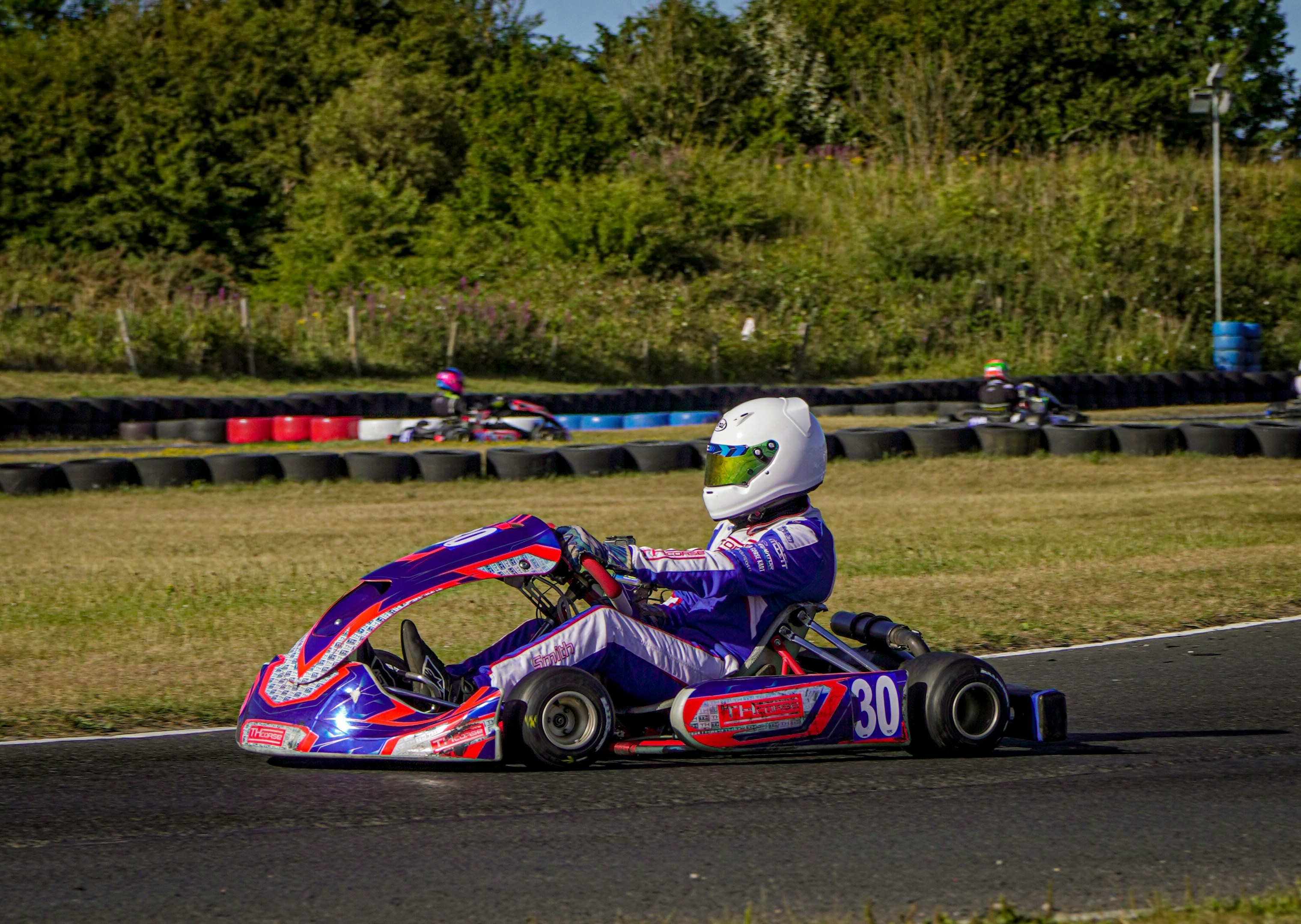 Purple go-kart in a sunlit sprint along a tight karting circuit