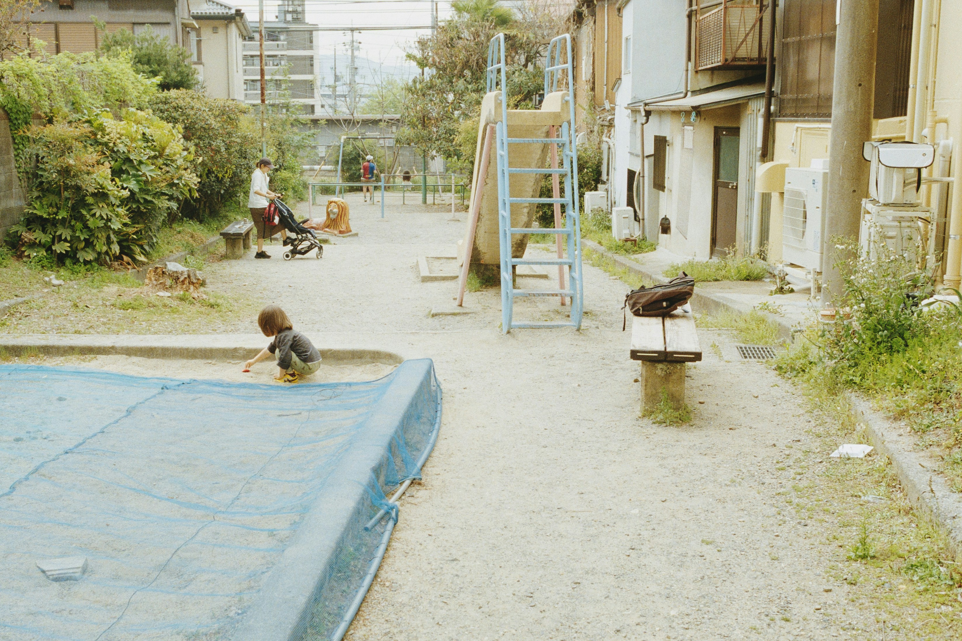 🎞️ Alien Film CN400 ProMax｜🧪 Fuji Hunt C-41｜🖨️ EOS R6 + RF 100mm f/2.8L Macro｜📷 Canon New F-1 + FD 35mm 1:2 S.S.C. | A child plays in a sandy playground.