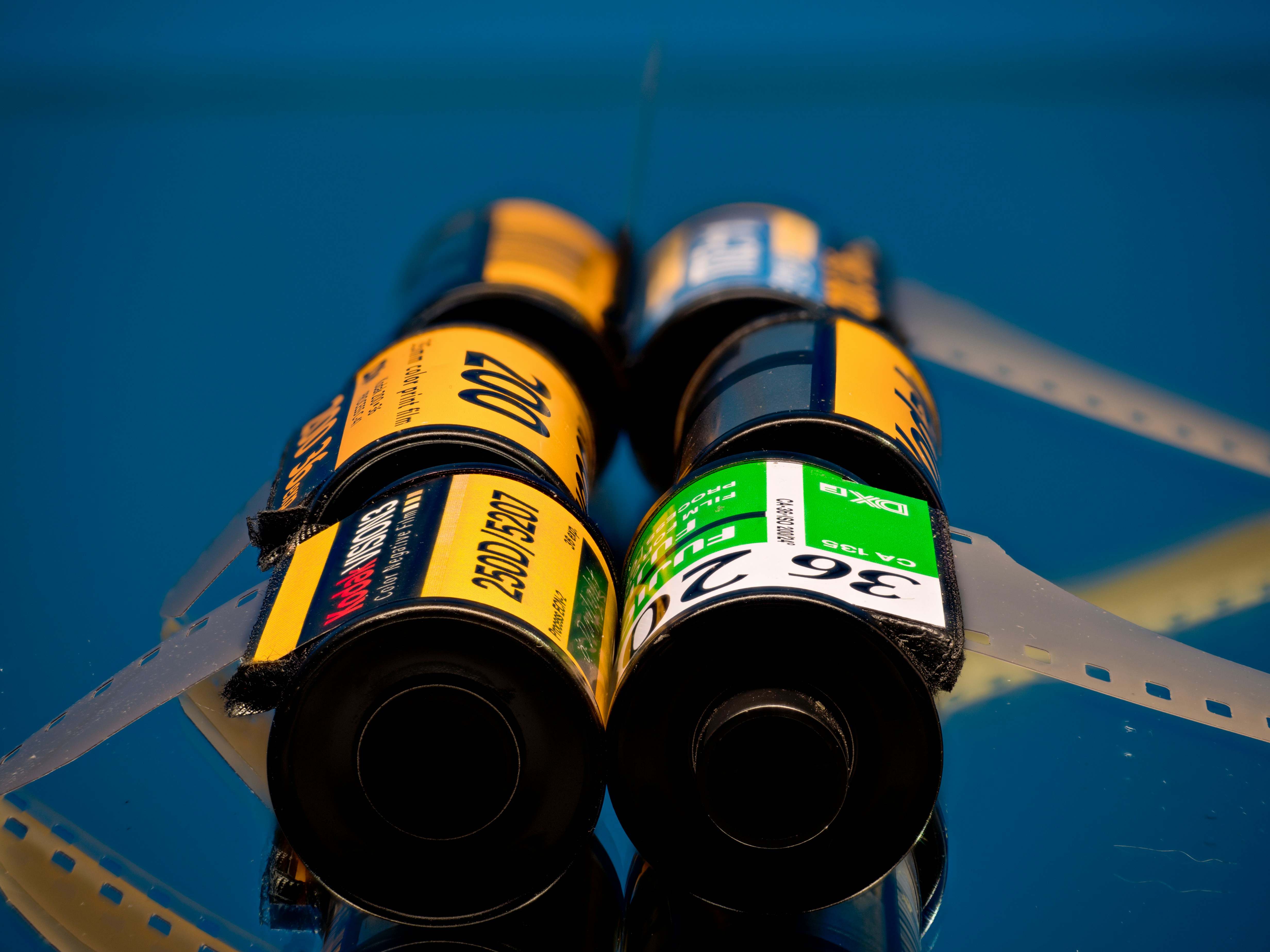 Film rolls are stacked on a reflective, blue surface.