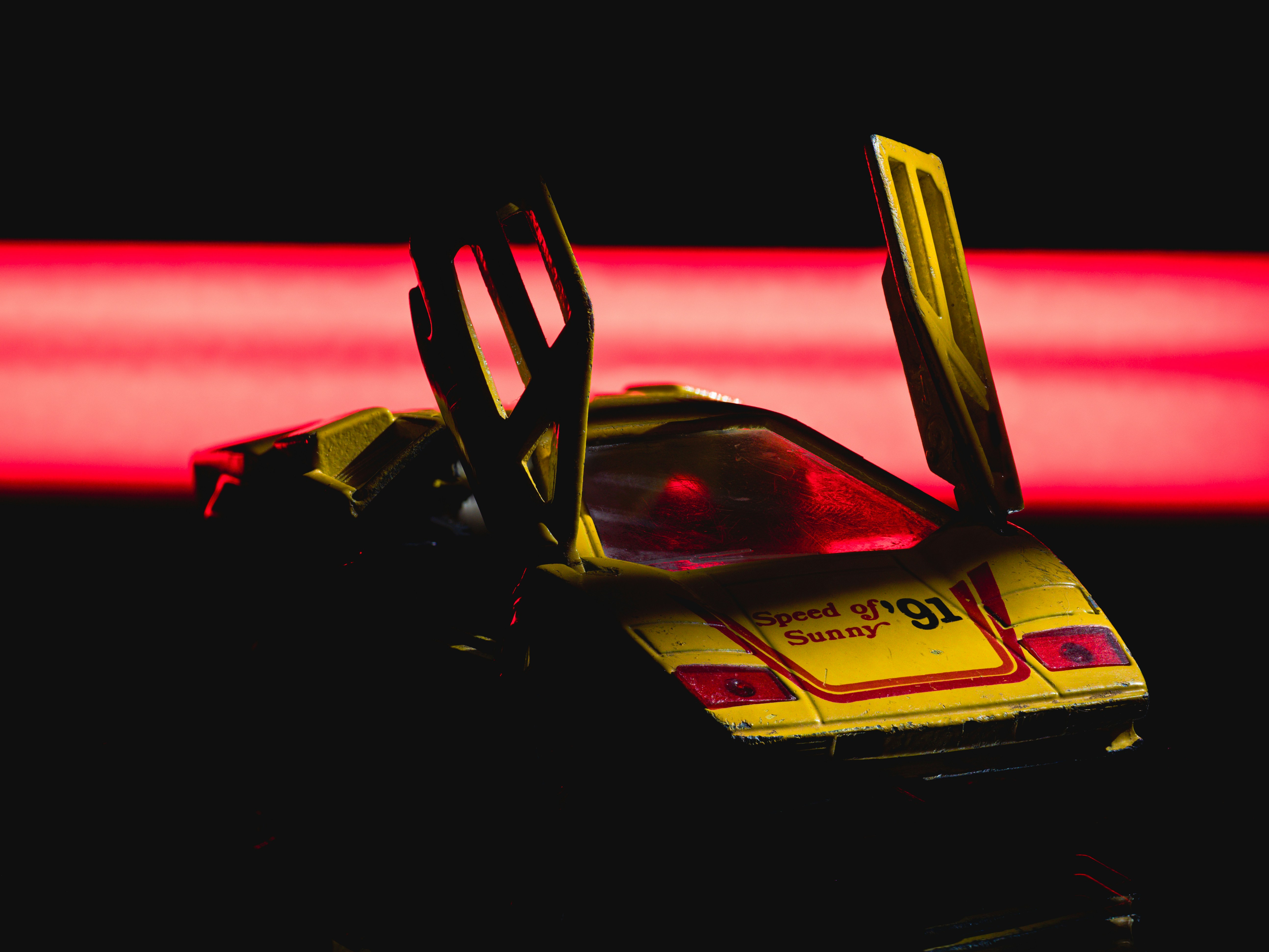 Yellow toy car with its doors open.