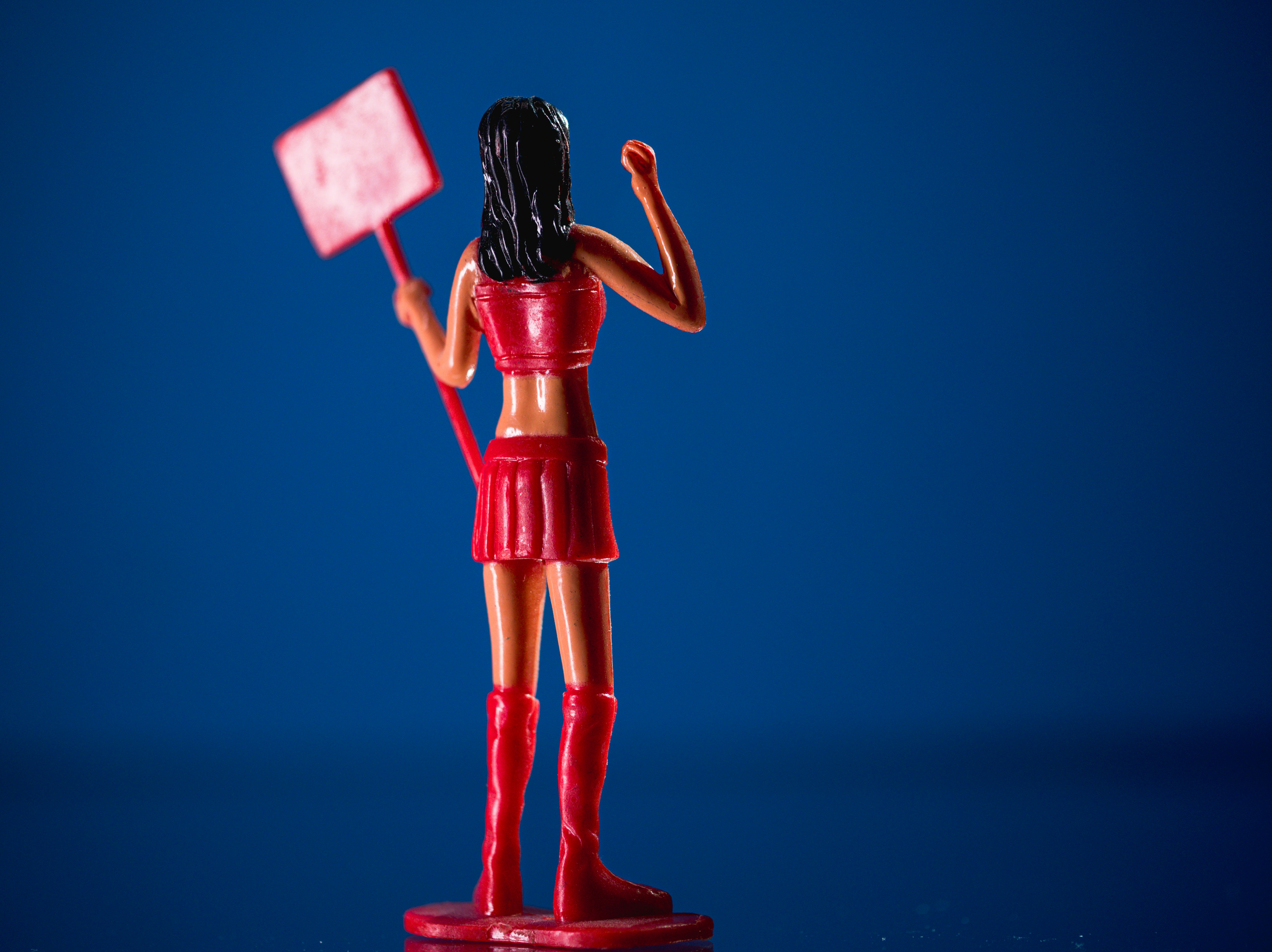 A toy cheerleader holds a red sign.