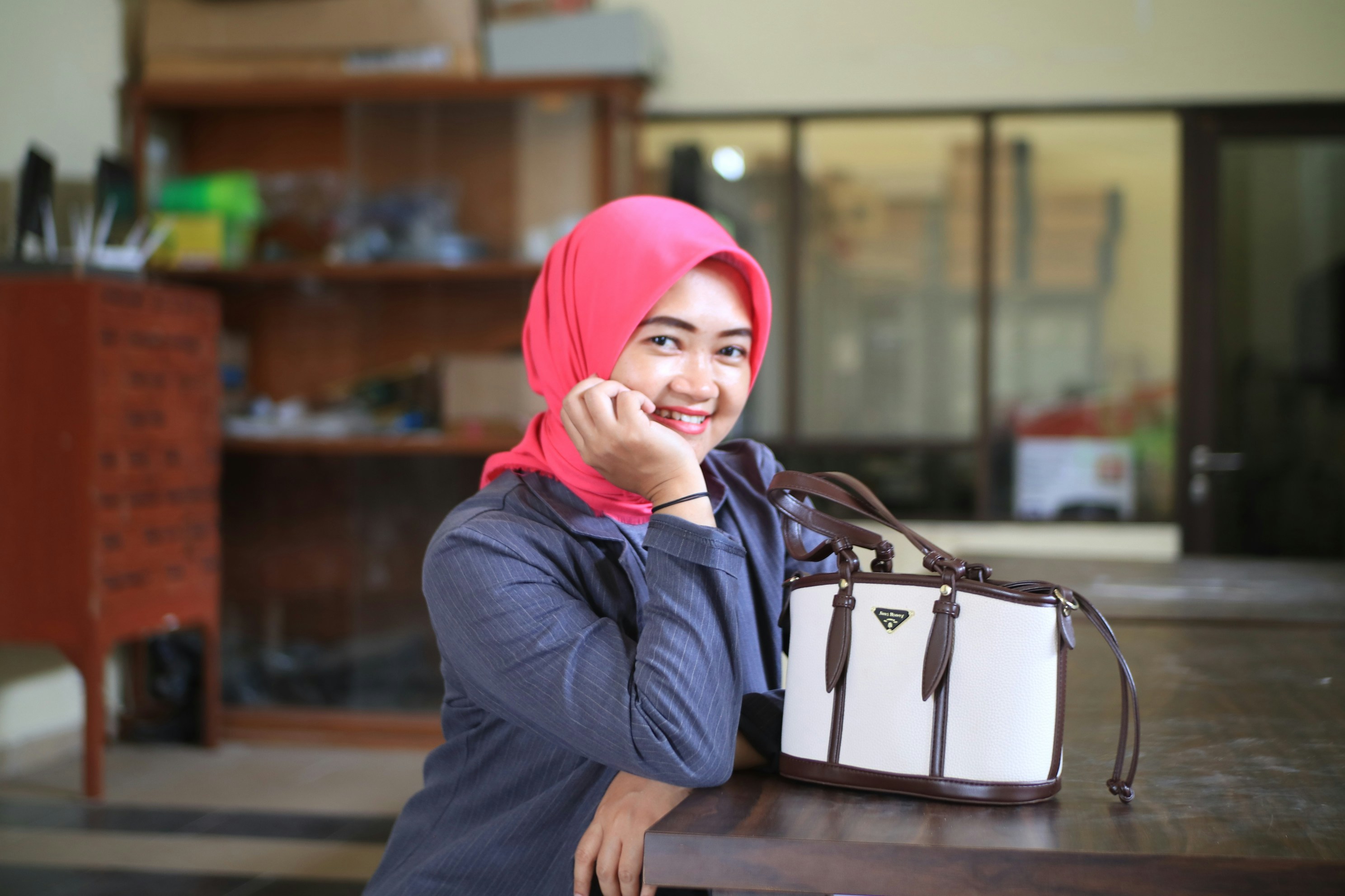 A smiling woman is posing with a purse.