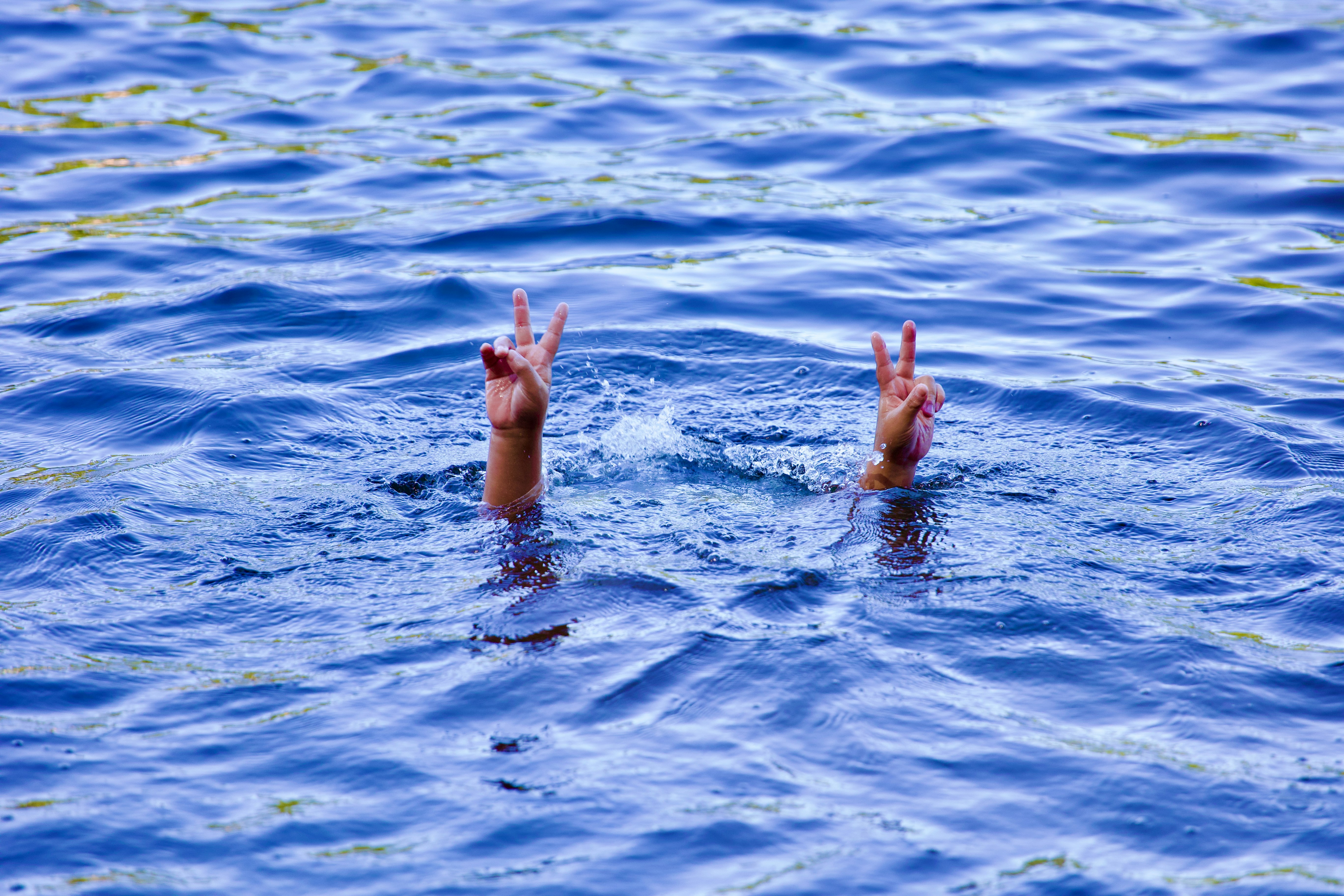 Giving peace signs while having fun at a lake in North Idaho. | Hands emerge from the water, signaling for help.