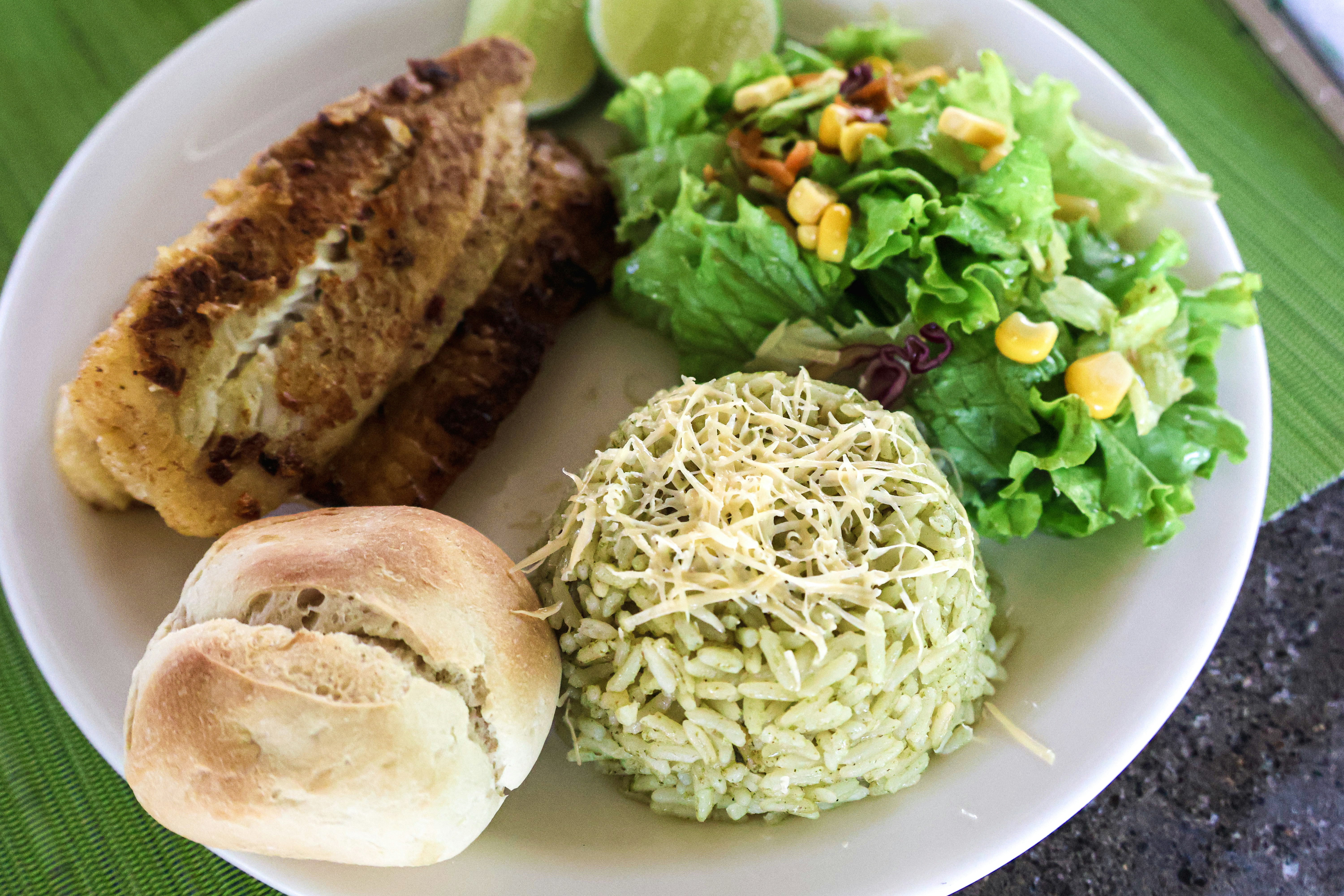 A delicious meal with fish, rice, salad, and bread.