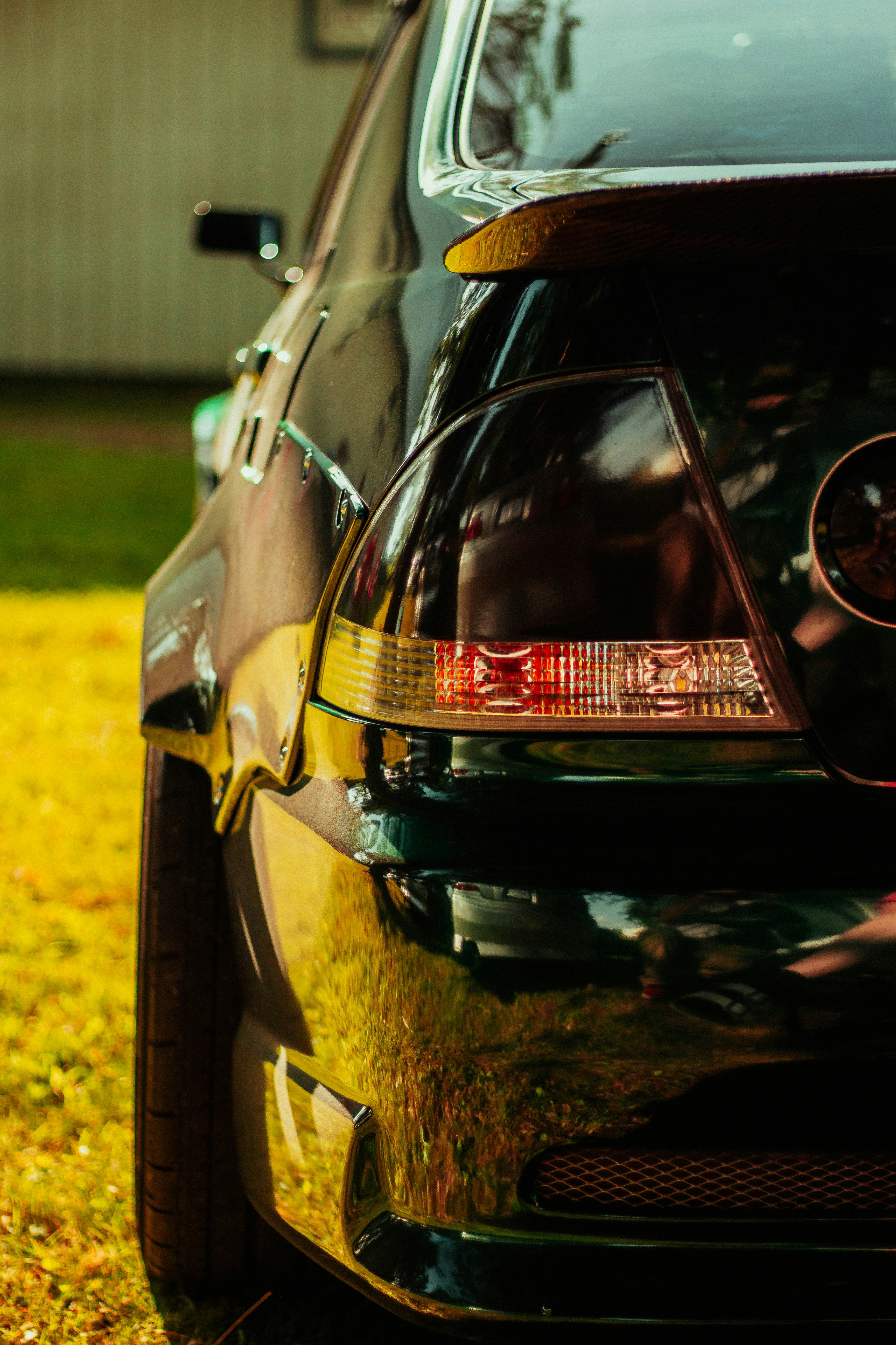 Here's a caption: black car's taillight shines in the sunlight.