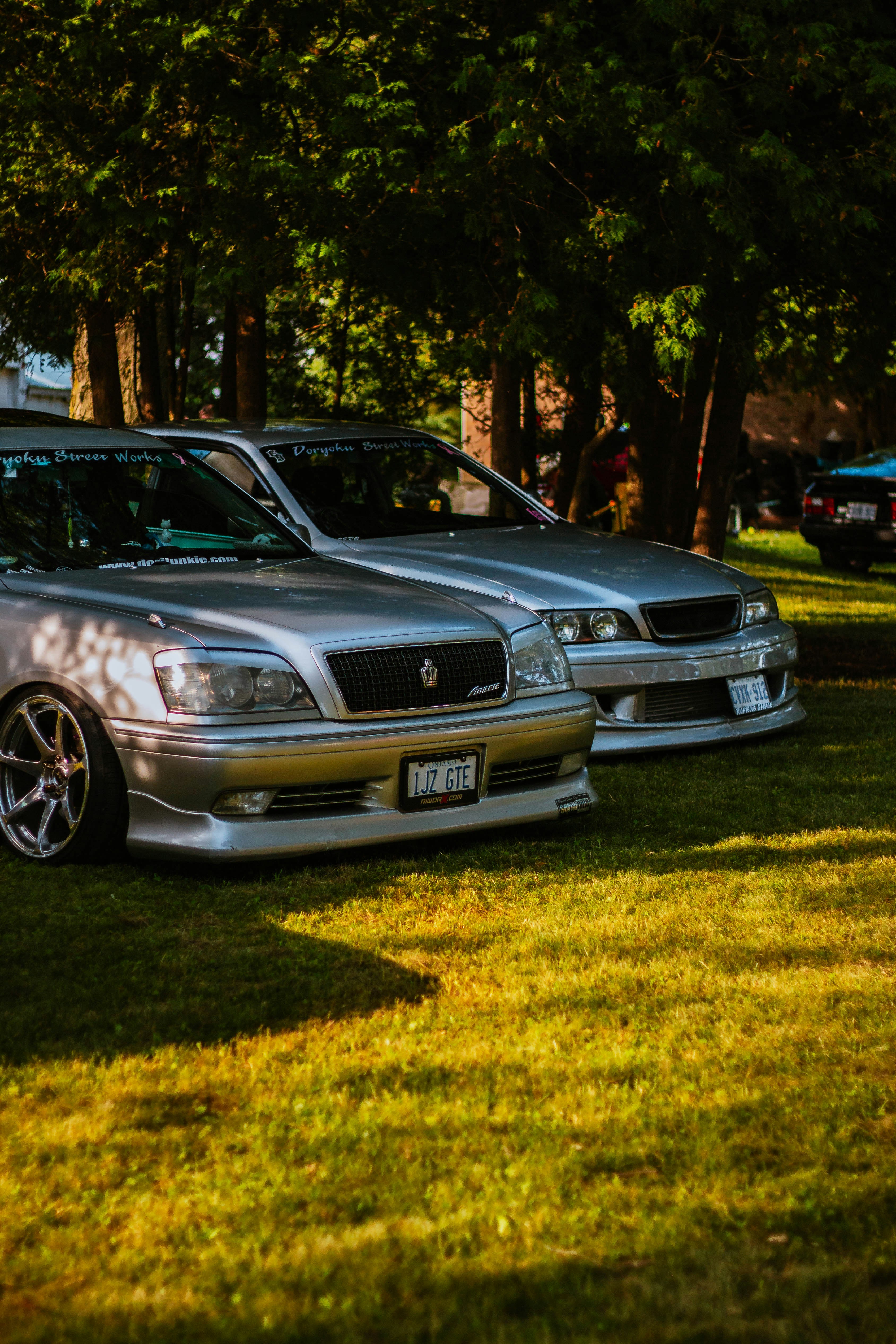 Two gray cars are parked on a grassy lawn. photo – Free Car Image on ...