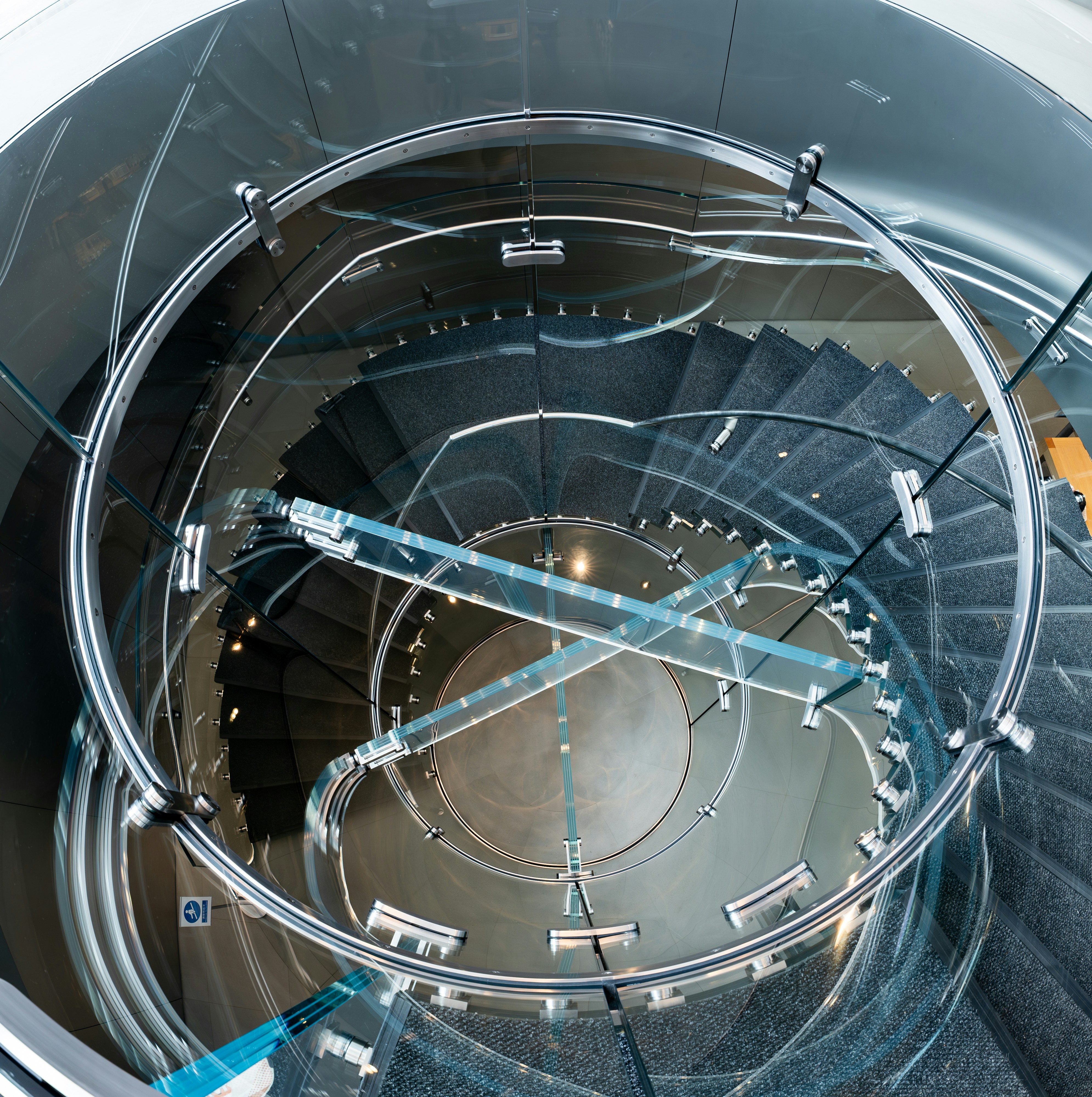 Vertical Helix: Top-Down Glimpse of a Glass-Walled Spiral Staircase