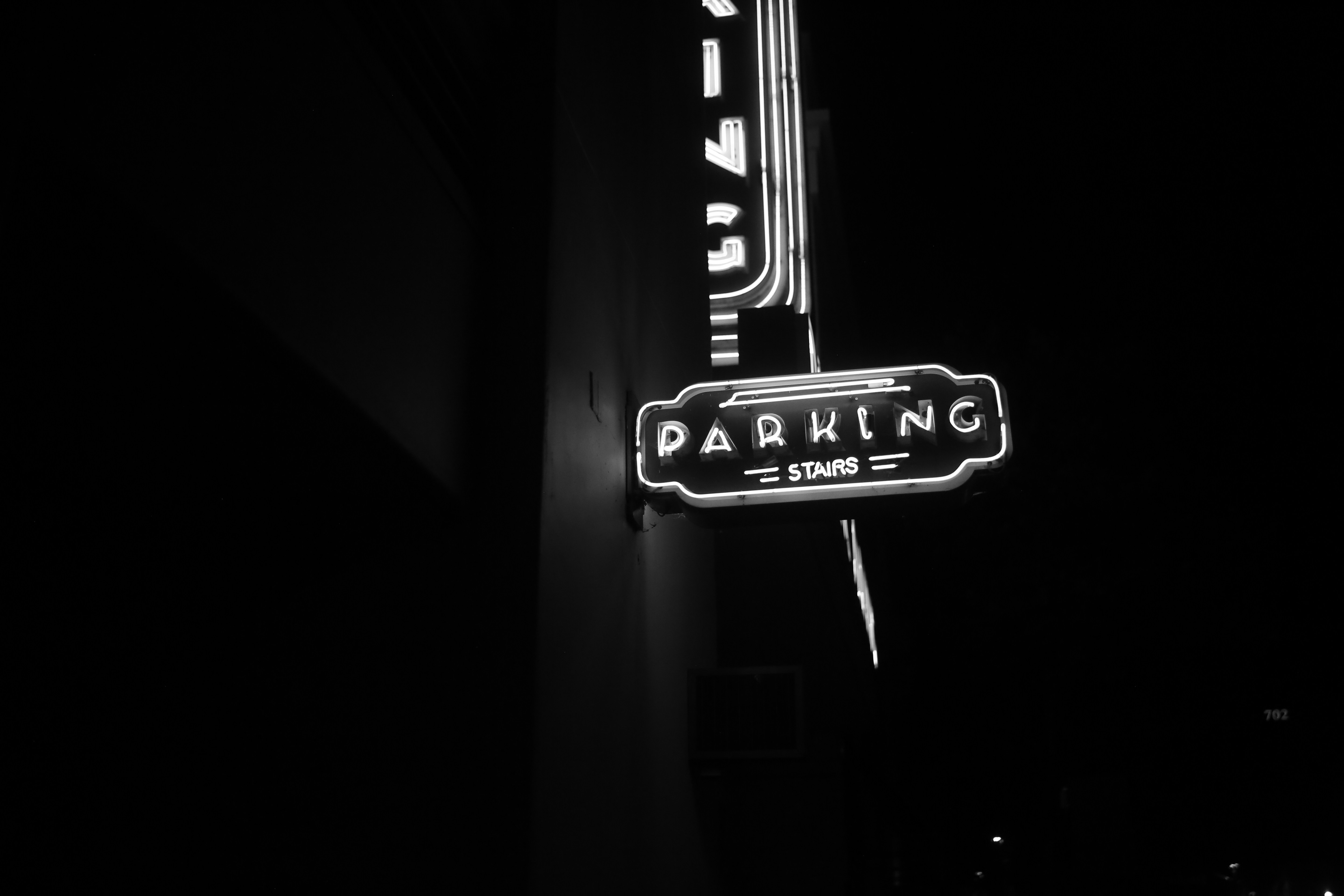 Neon parking sign glows at night.