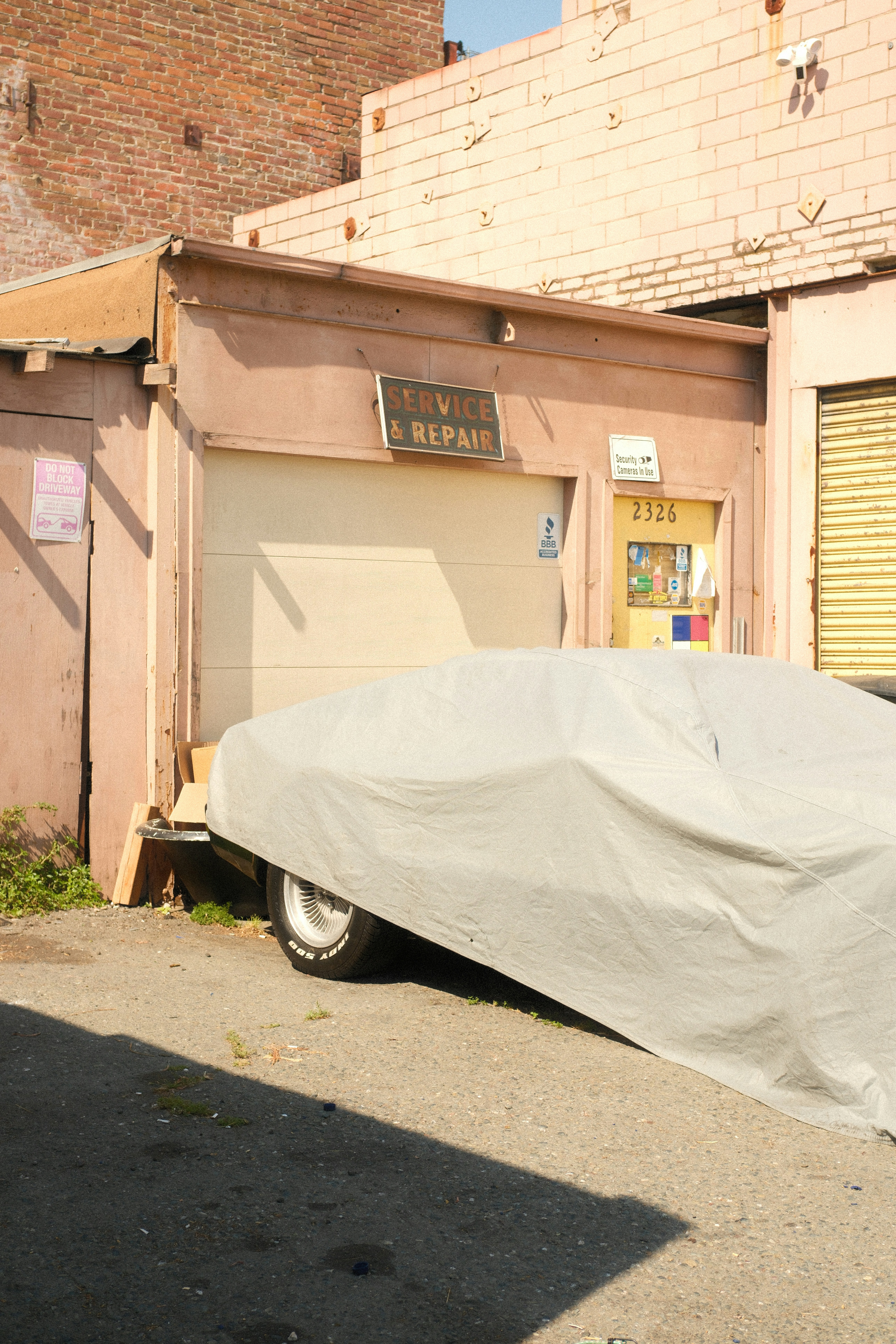 A covered car sits outside a repair shop. photo – Free Street ...