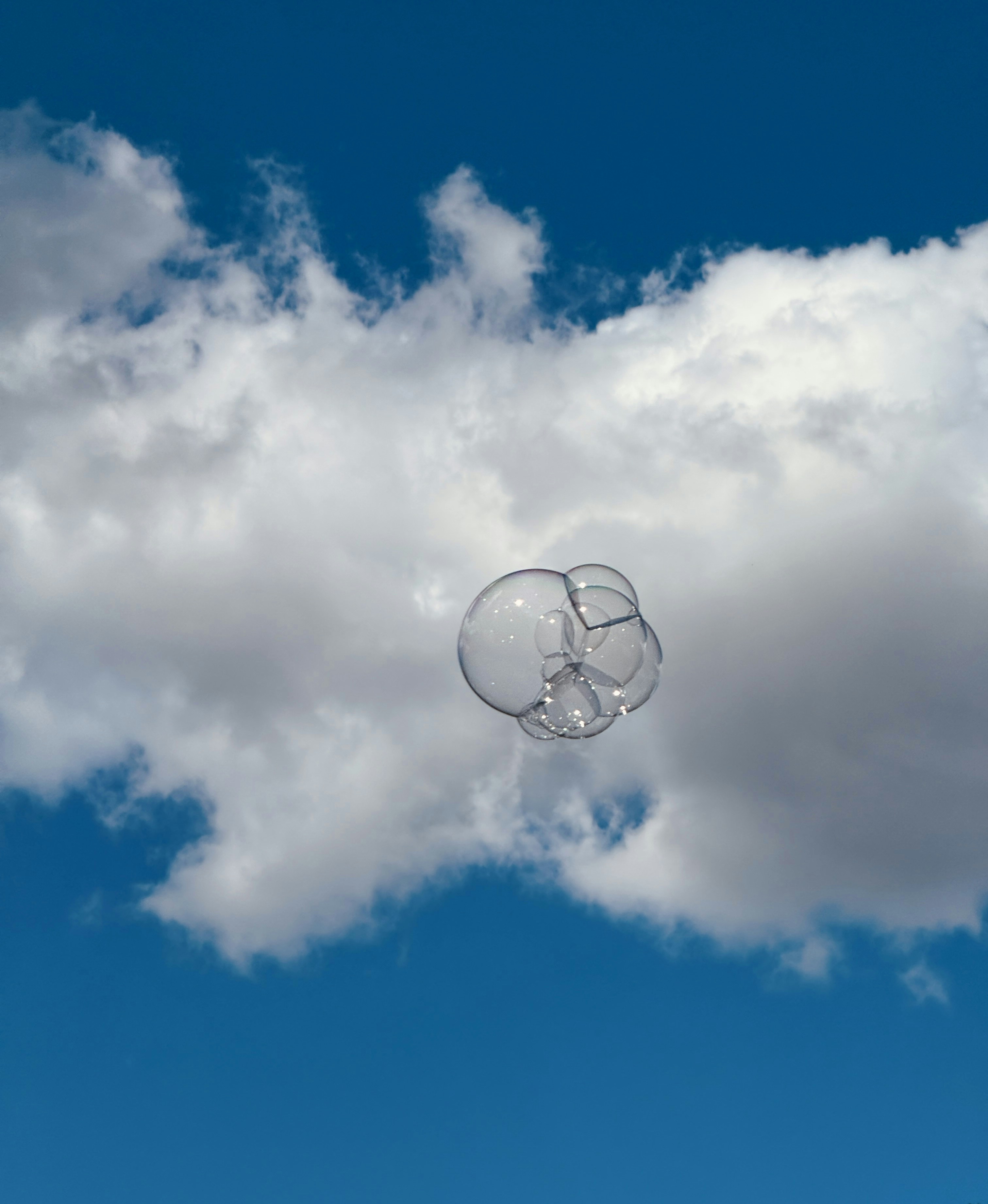 Bubbles float against a backdrop of clouds and sky.