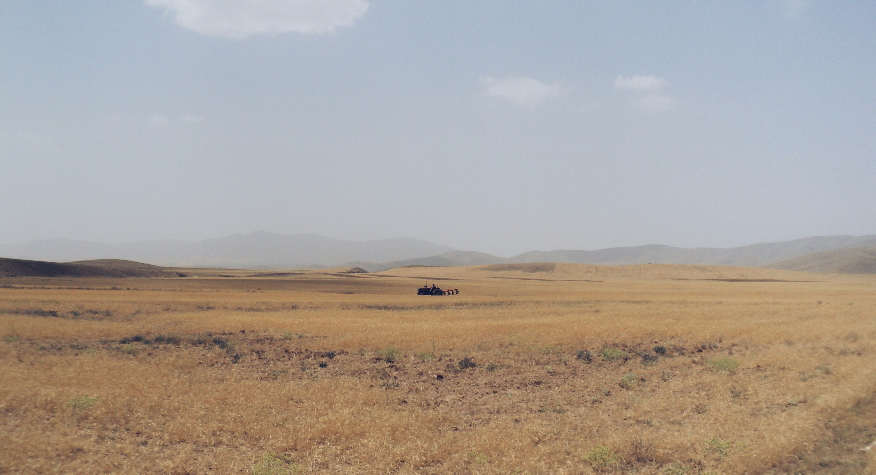 The only sound is the wind. | A car travels through a vast, dry field.