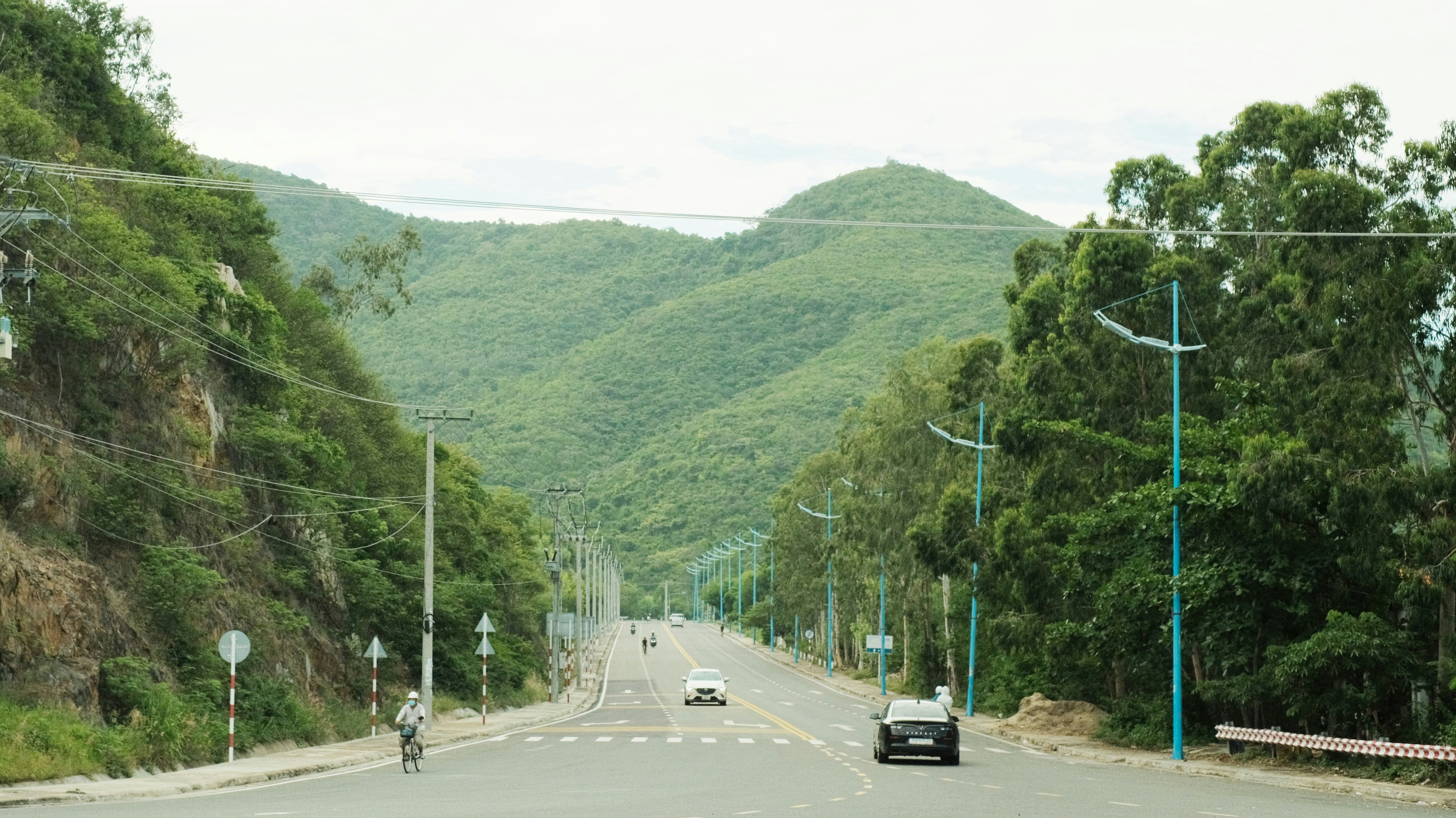 Nha Trang, quiet street in the morning! | A road winding through lush, green mountains.