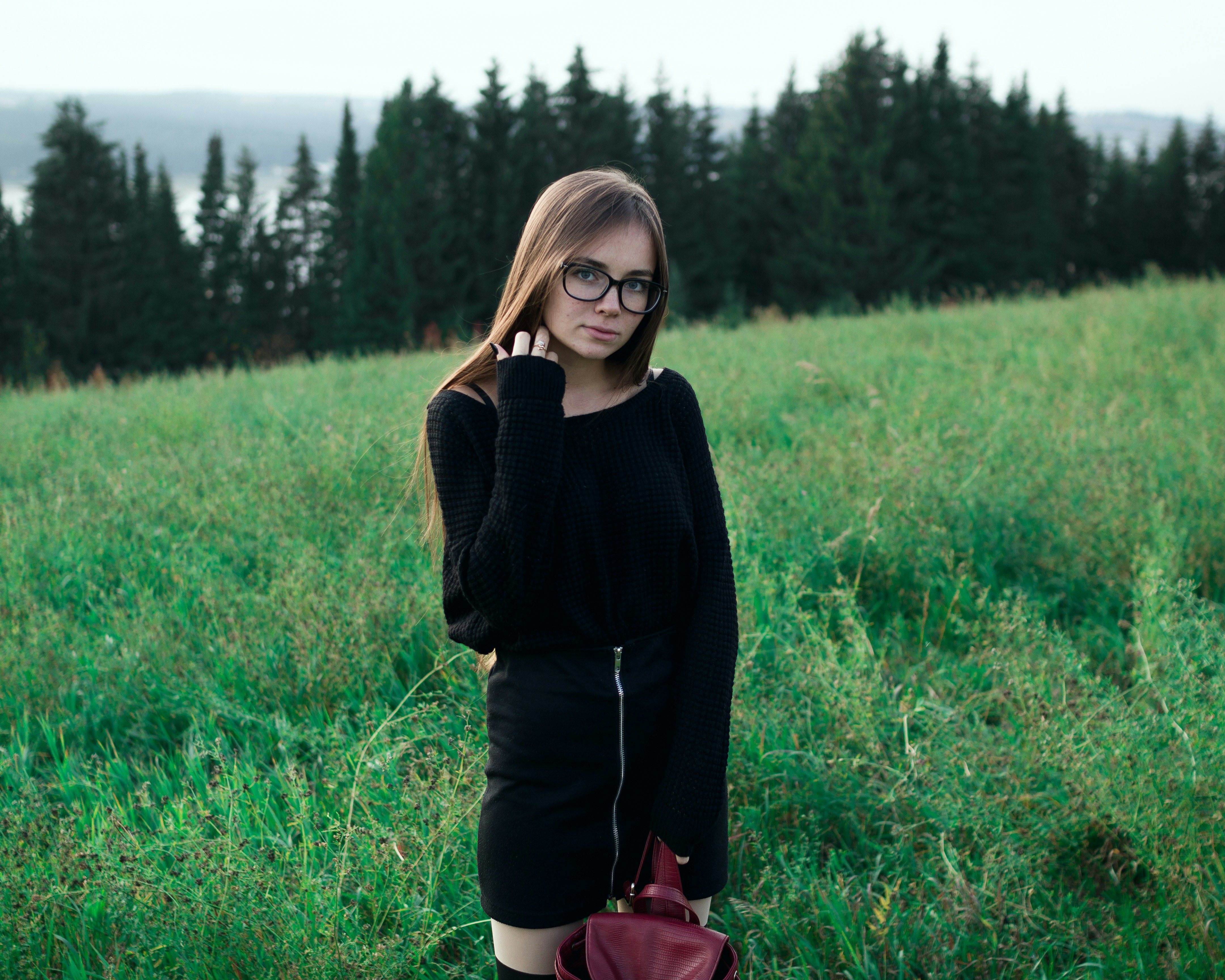 A woman poses in a grassy field.