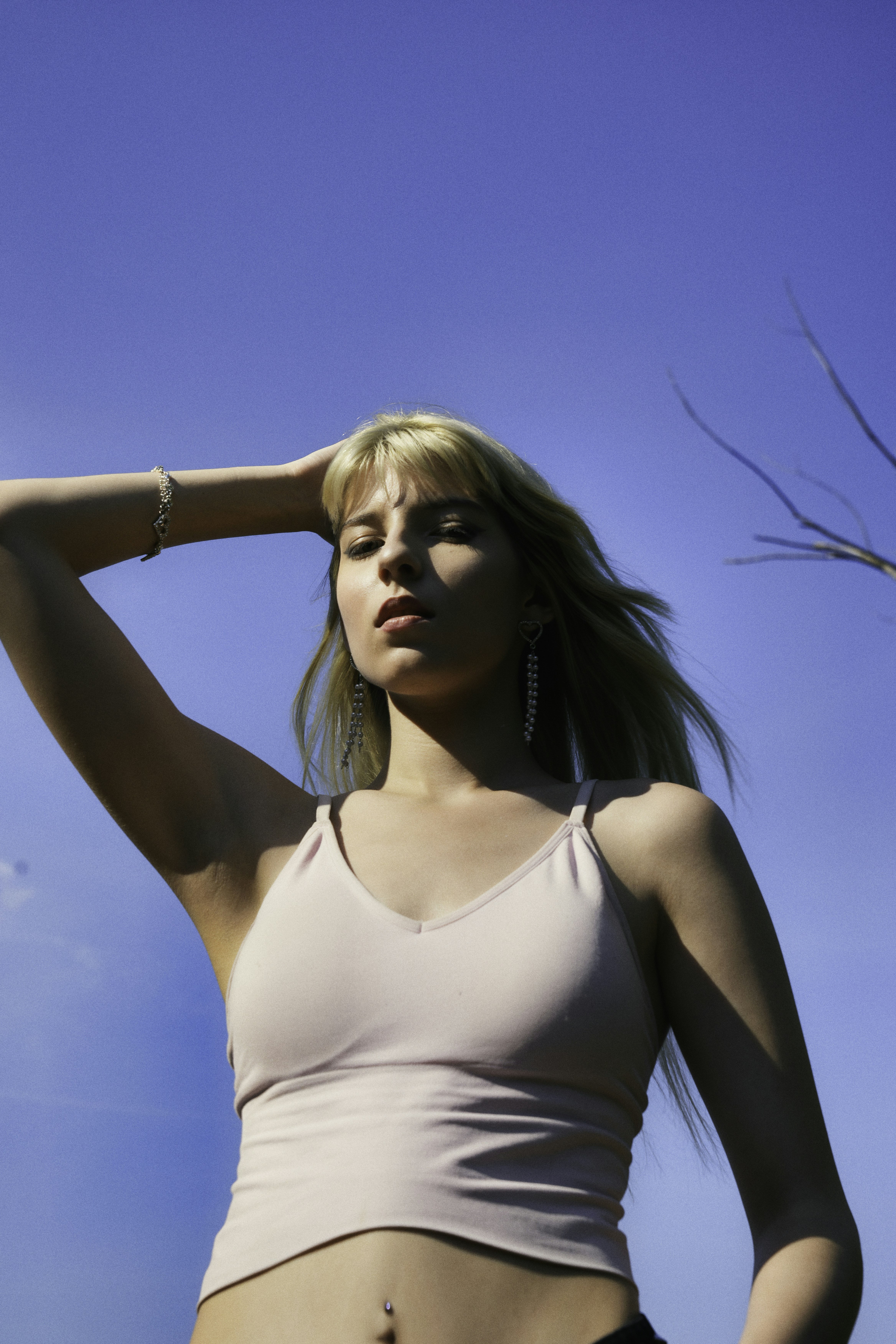 A woman poses against a blue sky.