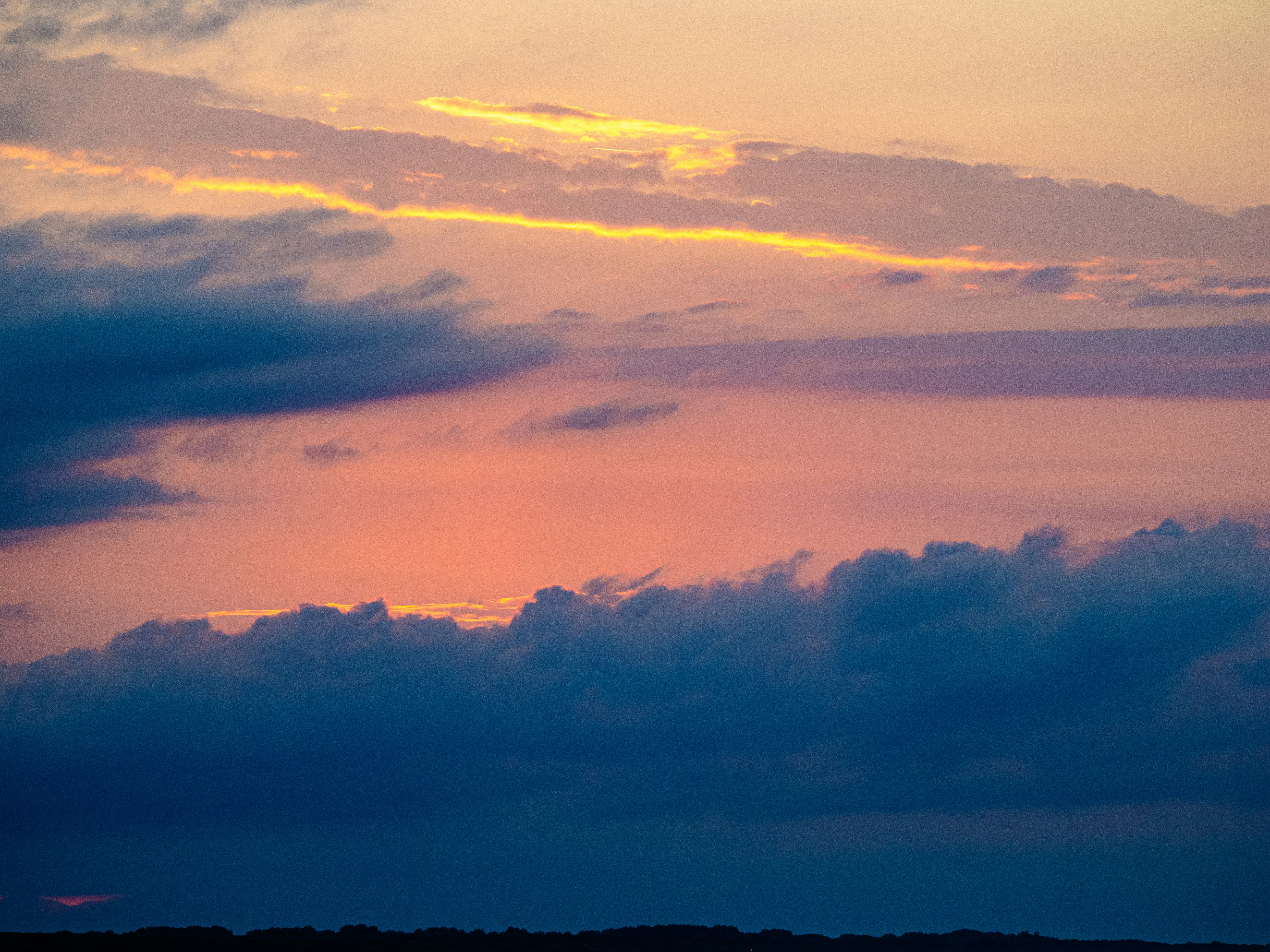A serene twilight sky painted with soft hues of pink and orange, contrasted by dark clouds. The horizon blends seamlessly, creating a tranquil atmosphere.