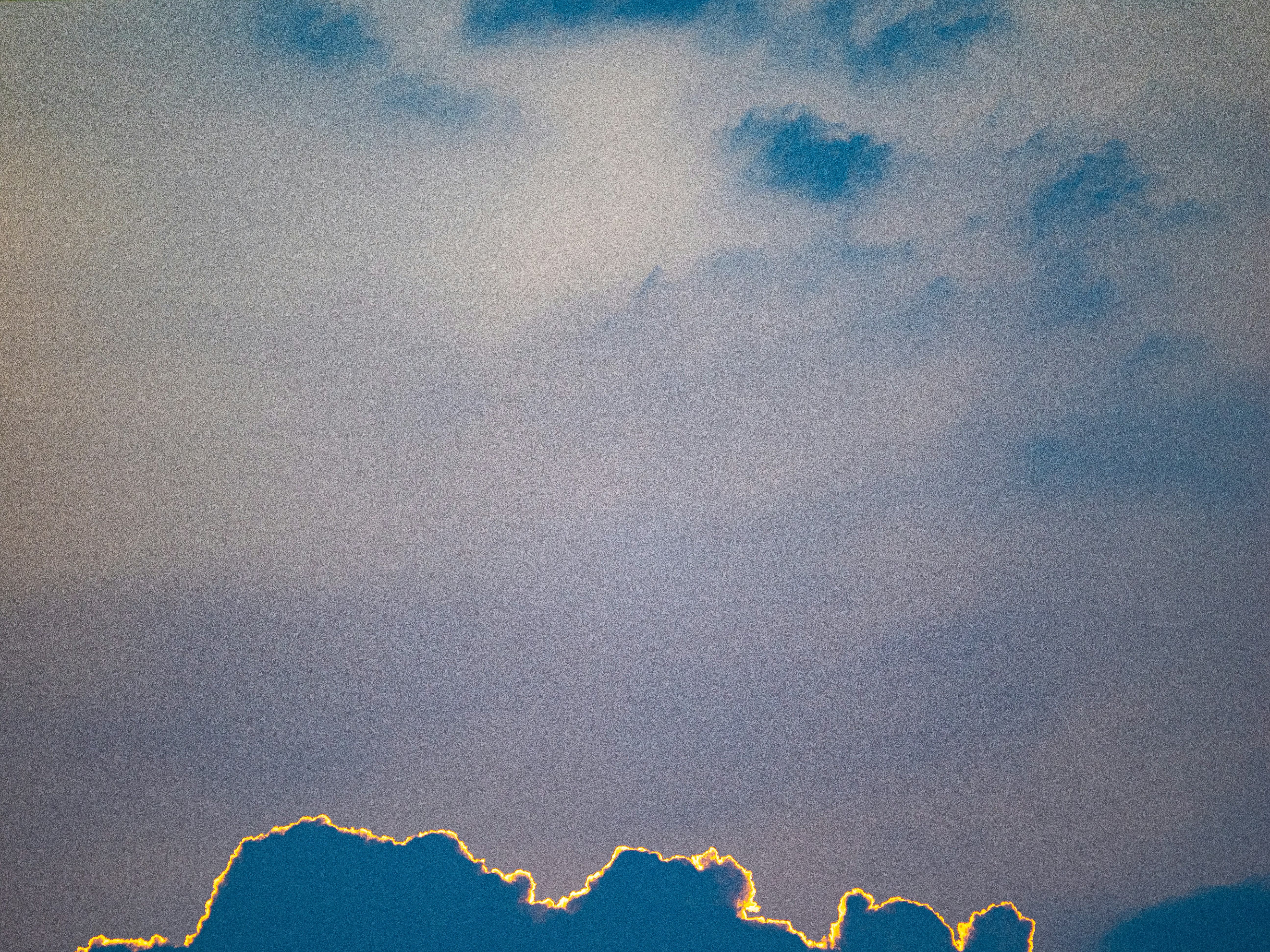Golden-edged clouds softly illuminated against a gradient sky at twilight.