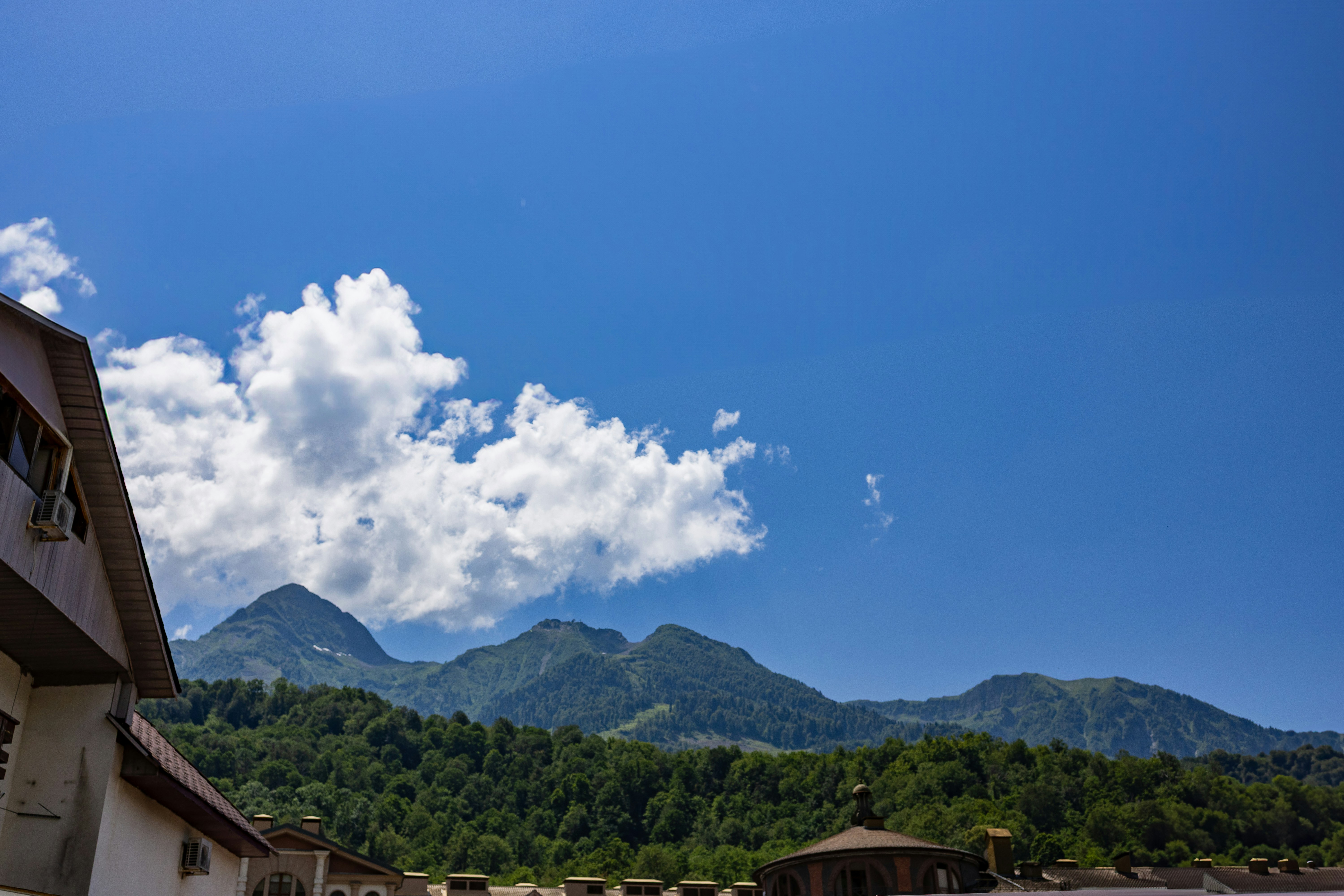 Mountains and a building beneath a bright blue sky.