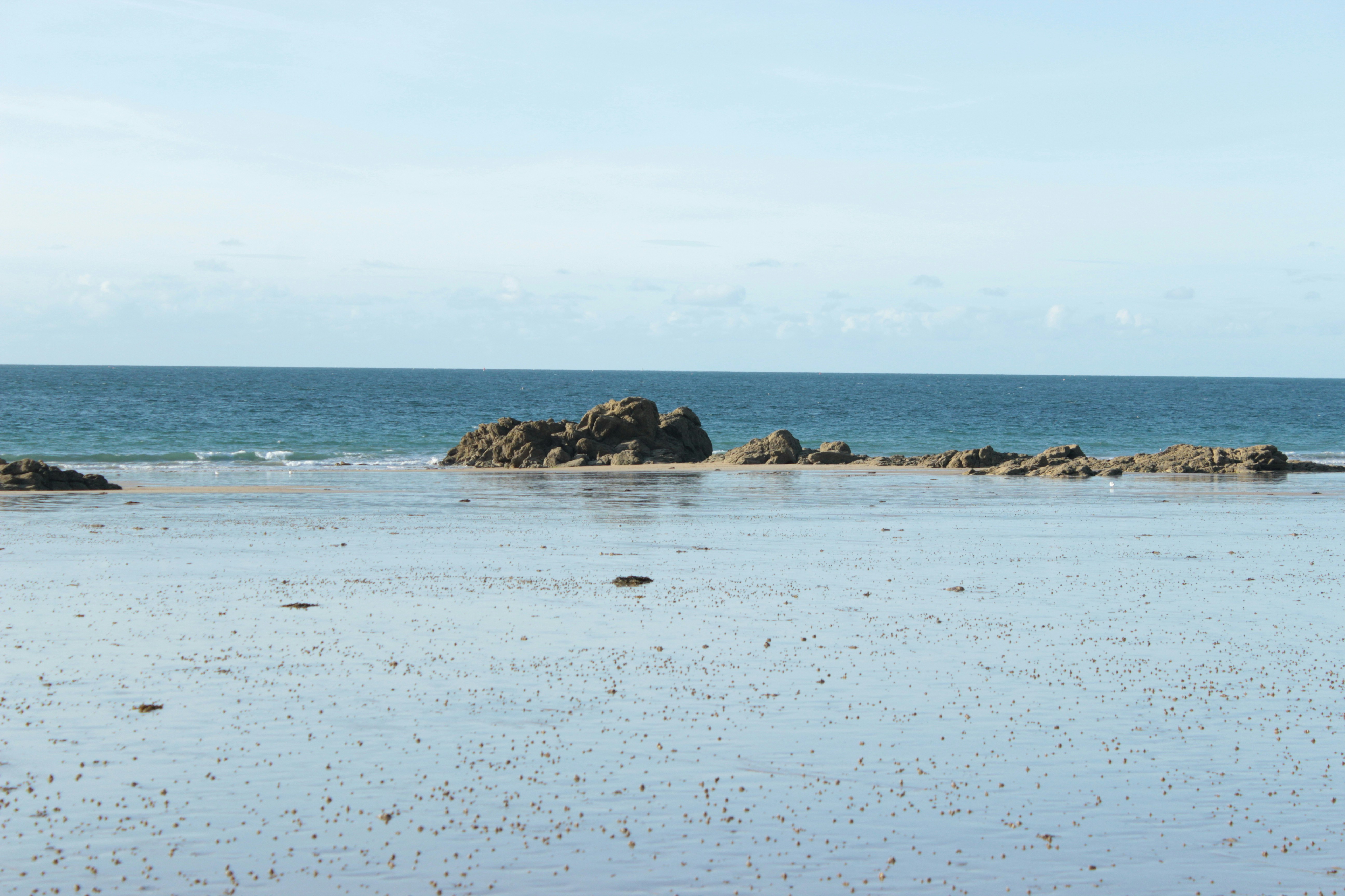 vue de la mer en Bretagne | Rocks sit in the ocean at low tide.