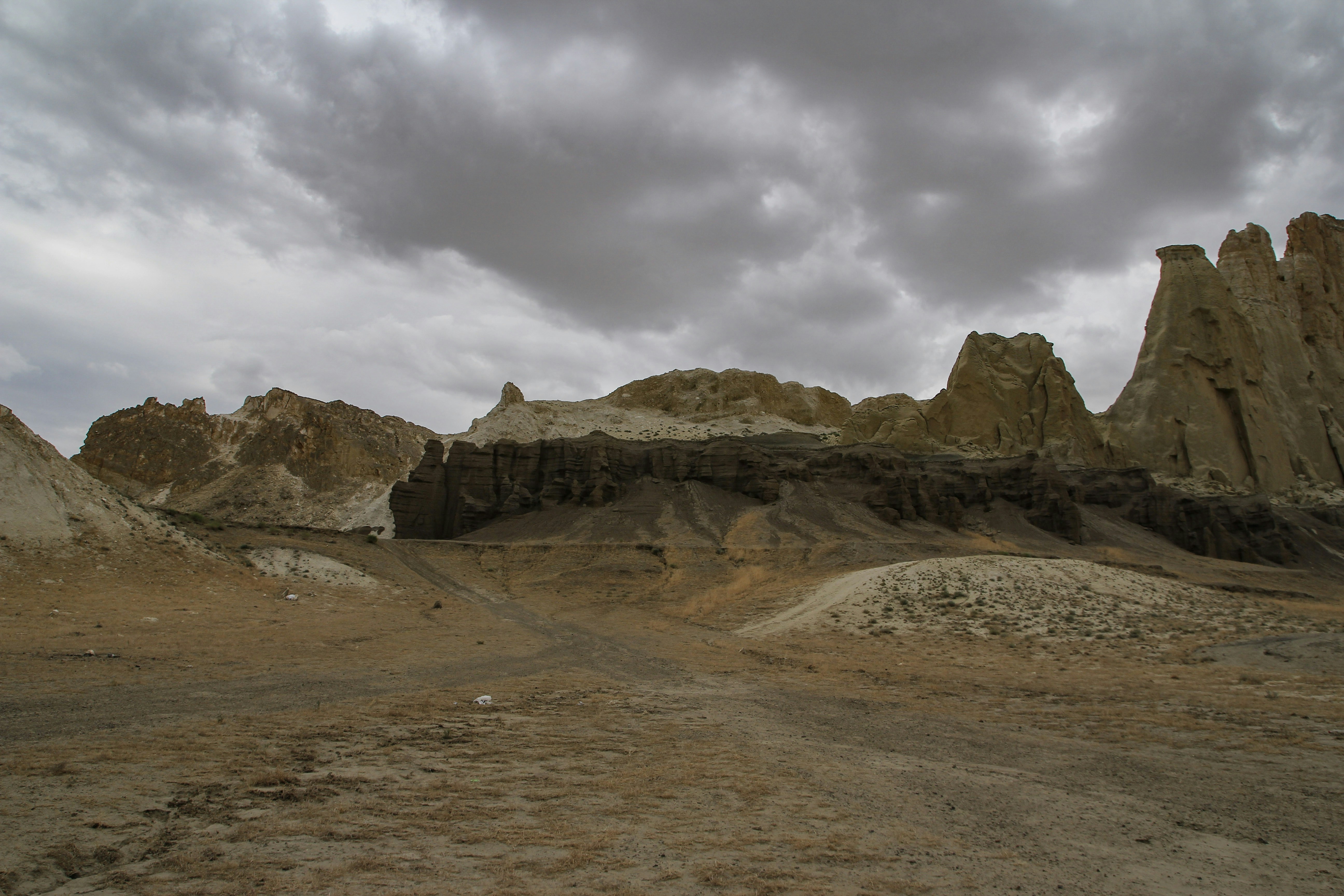 Eroded rock formations sit under a cloudy sky.