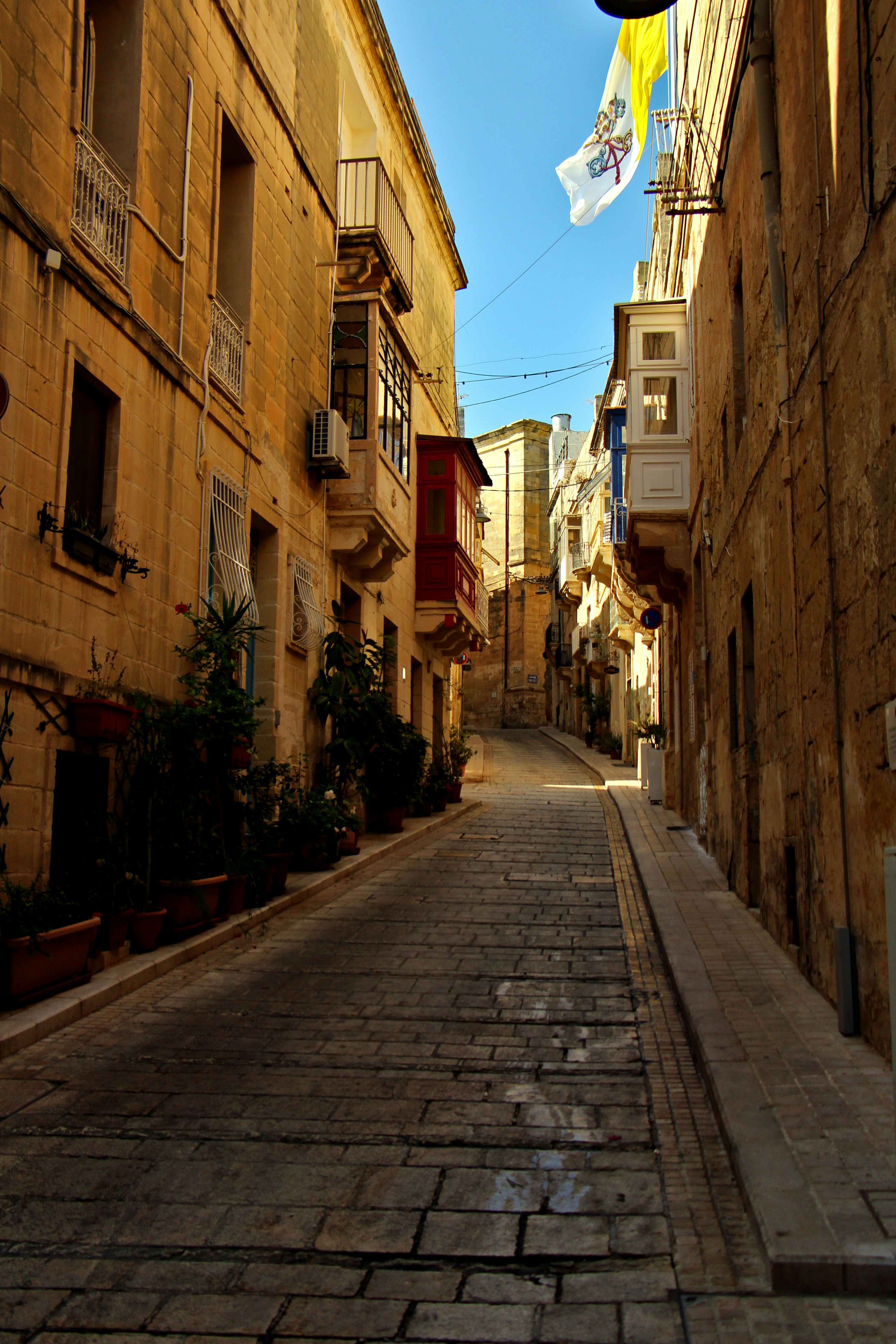 hot empty streets in the heart of summer | A narrow alleyway with stone buildings and sunshine.