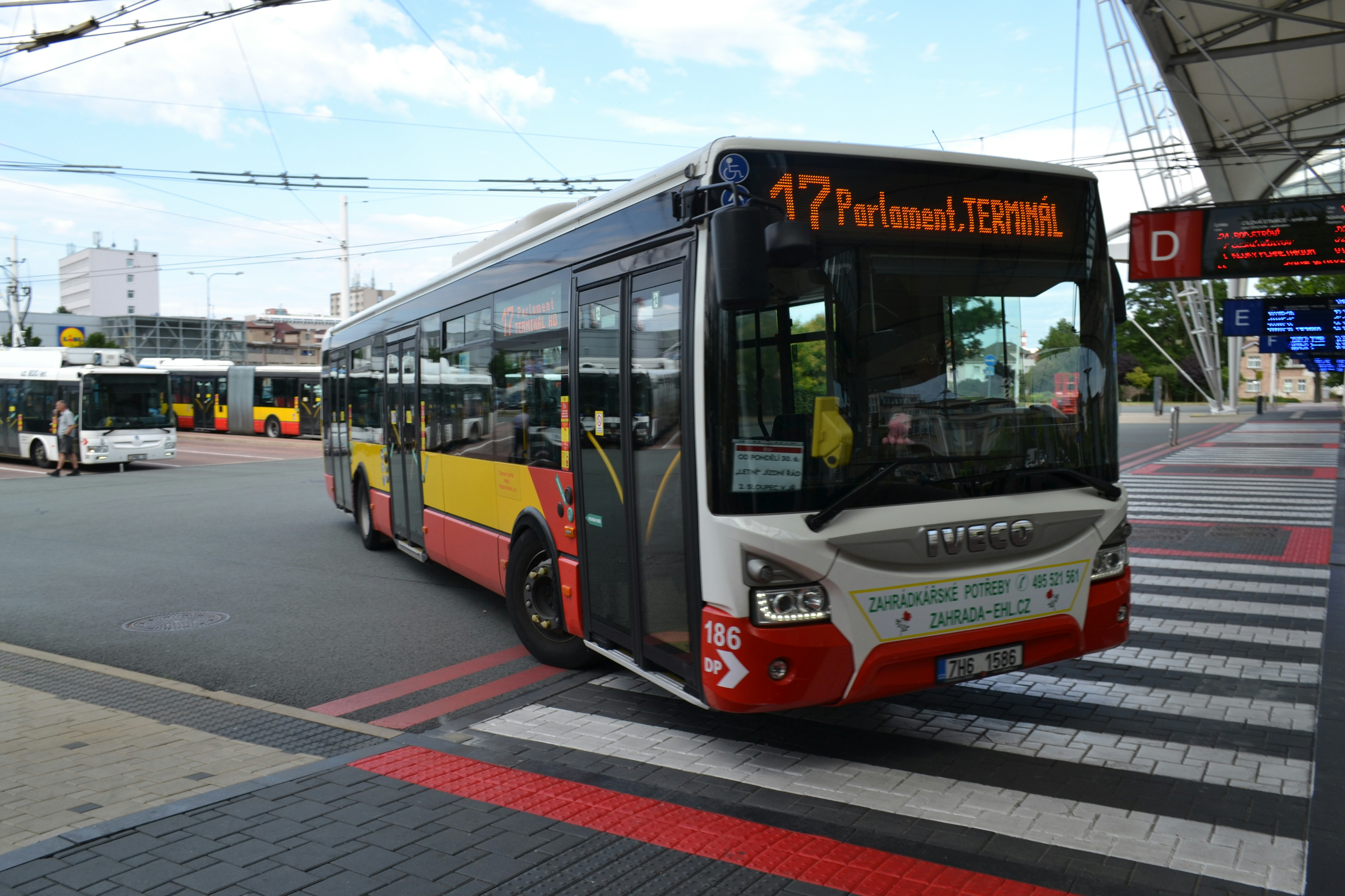 City bus arriving at a terminal, showcasing vibrant colors and urban infrastructure. The bus displays its route number prominently.