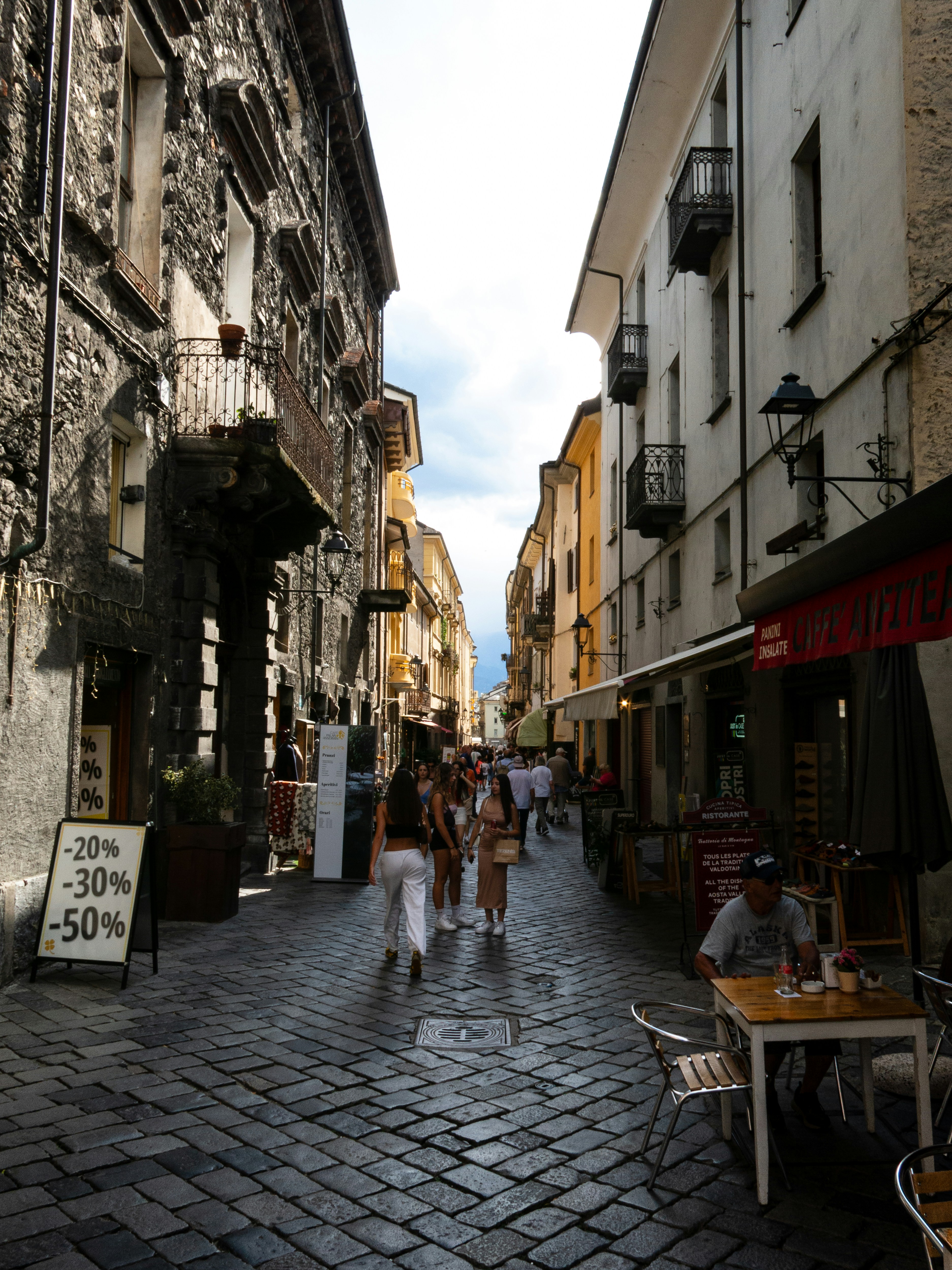 A cobblestone street with tourists and buildings.