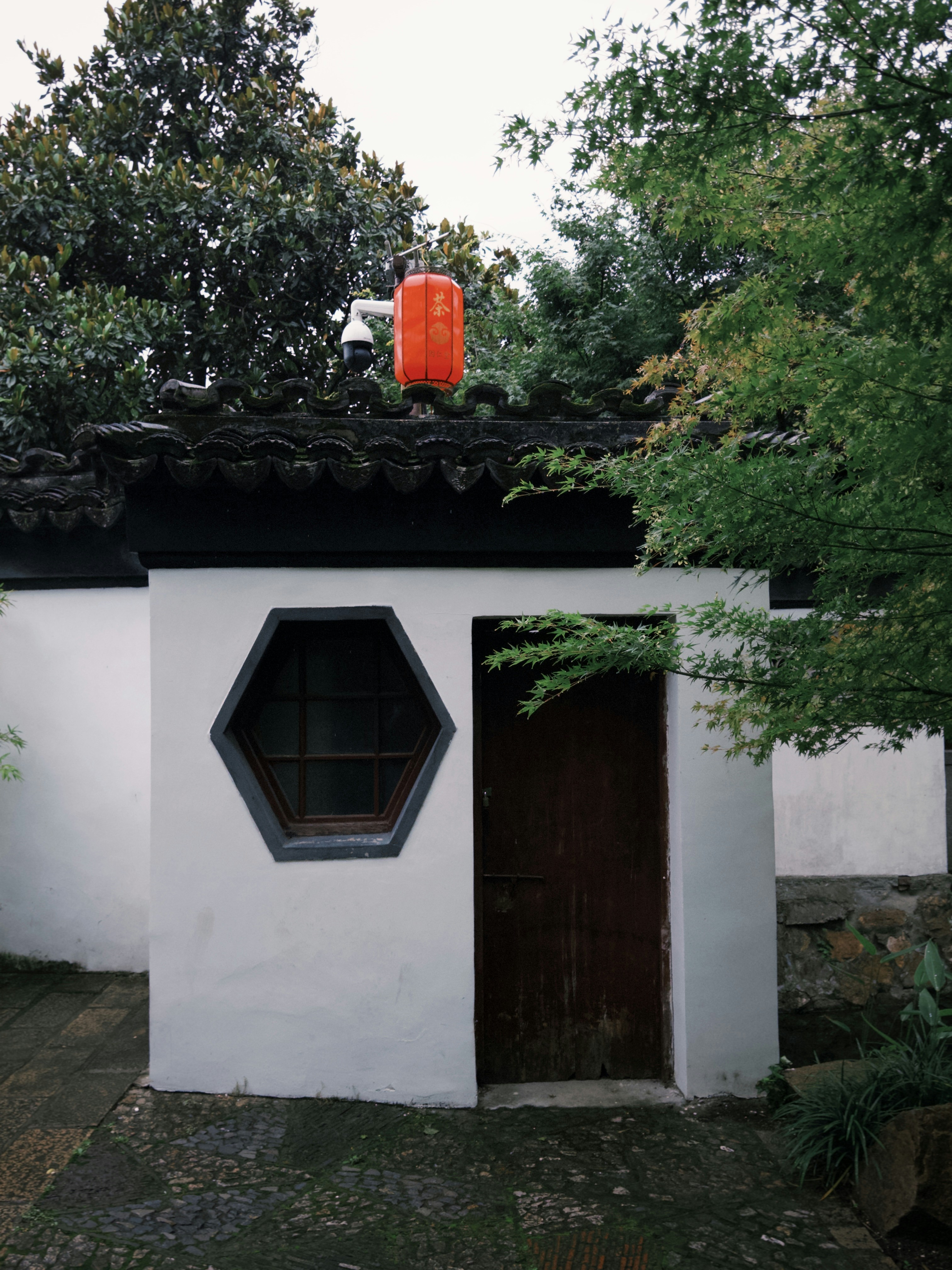 Crimson Lantern Above a White Hex Window Cottage in a Tranquil Garden