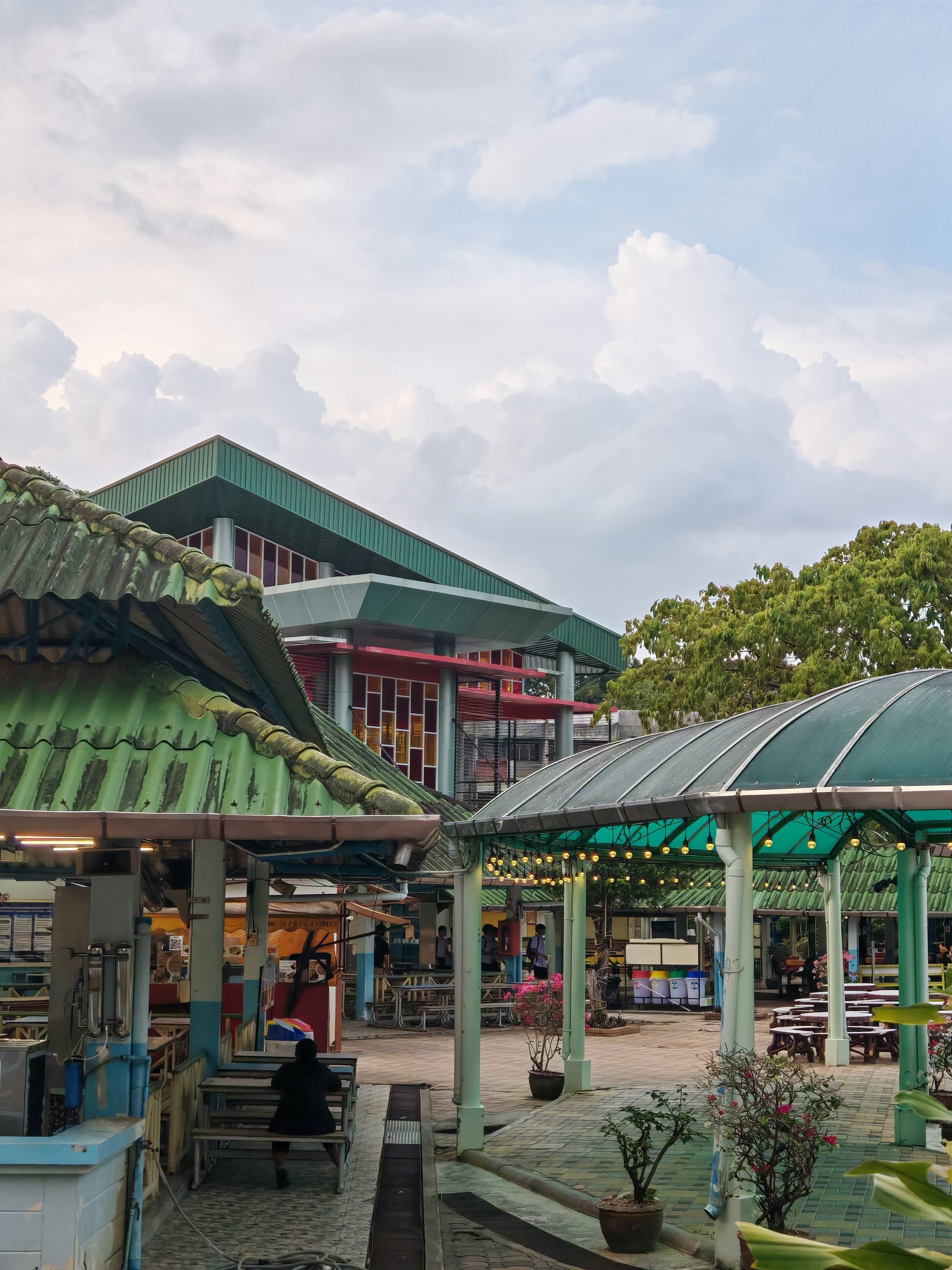 Outdoor marketplace with buildings under a cloudy sky.
