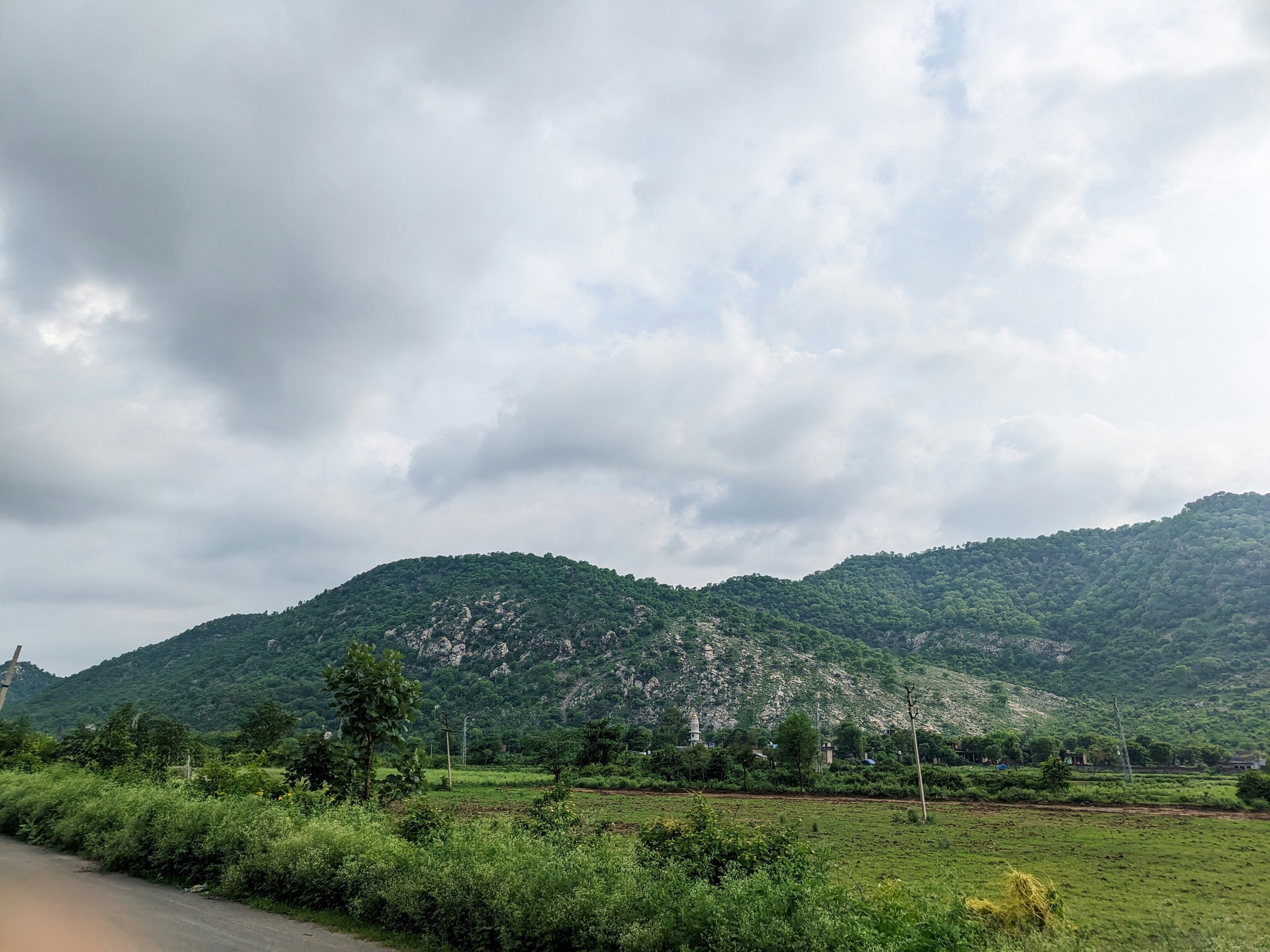 Green hills are under a cloudy sky.