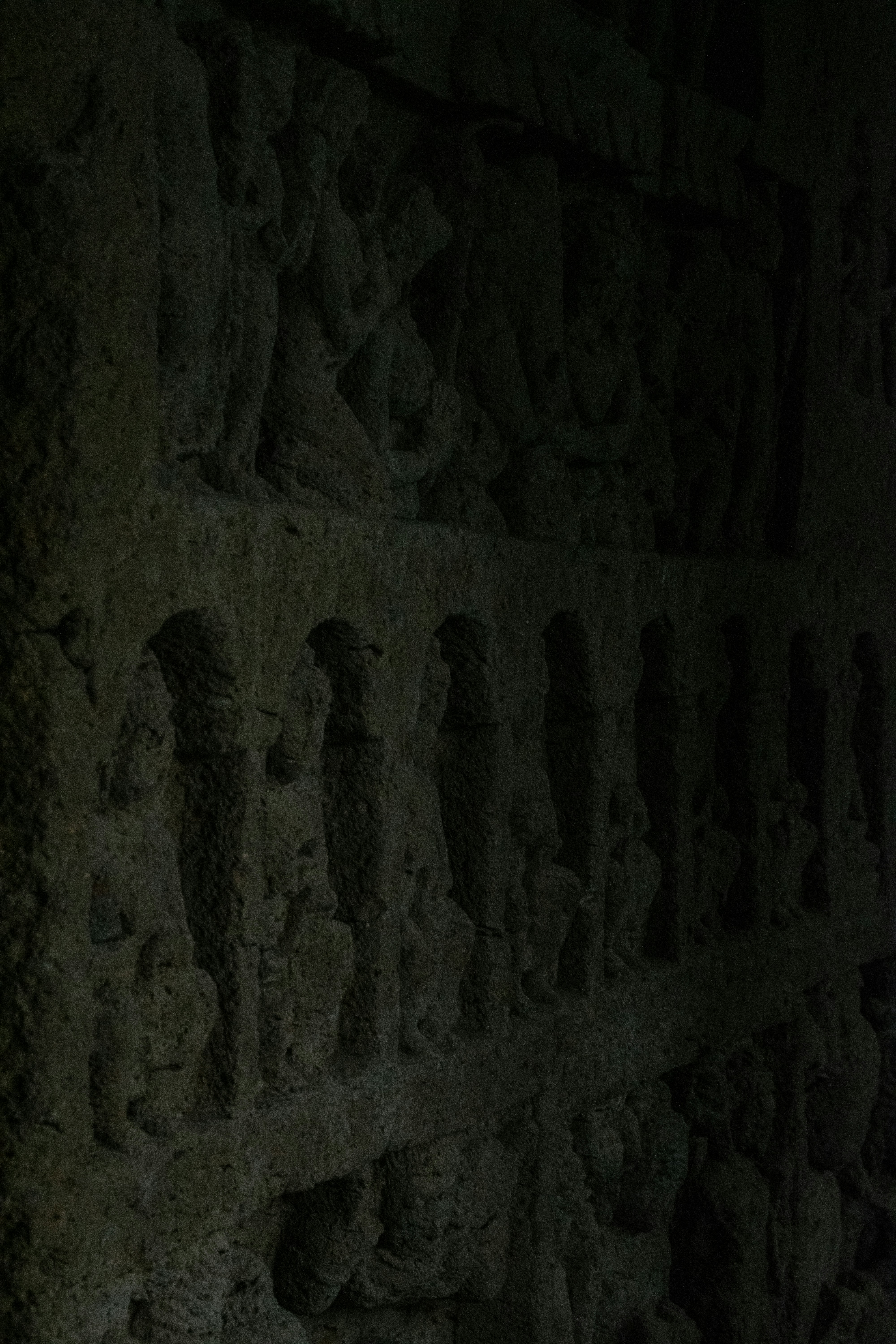carvings of buddha inside one of the many caves of the kanheri caves archeology site | Ancient stone carvings depicting figures are visible.