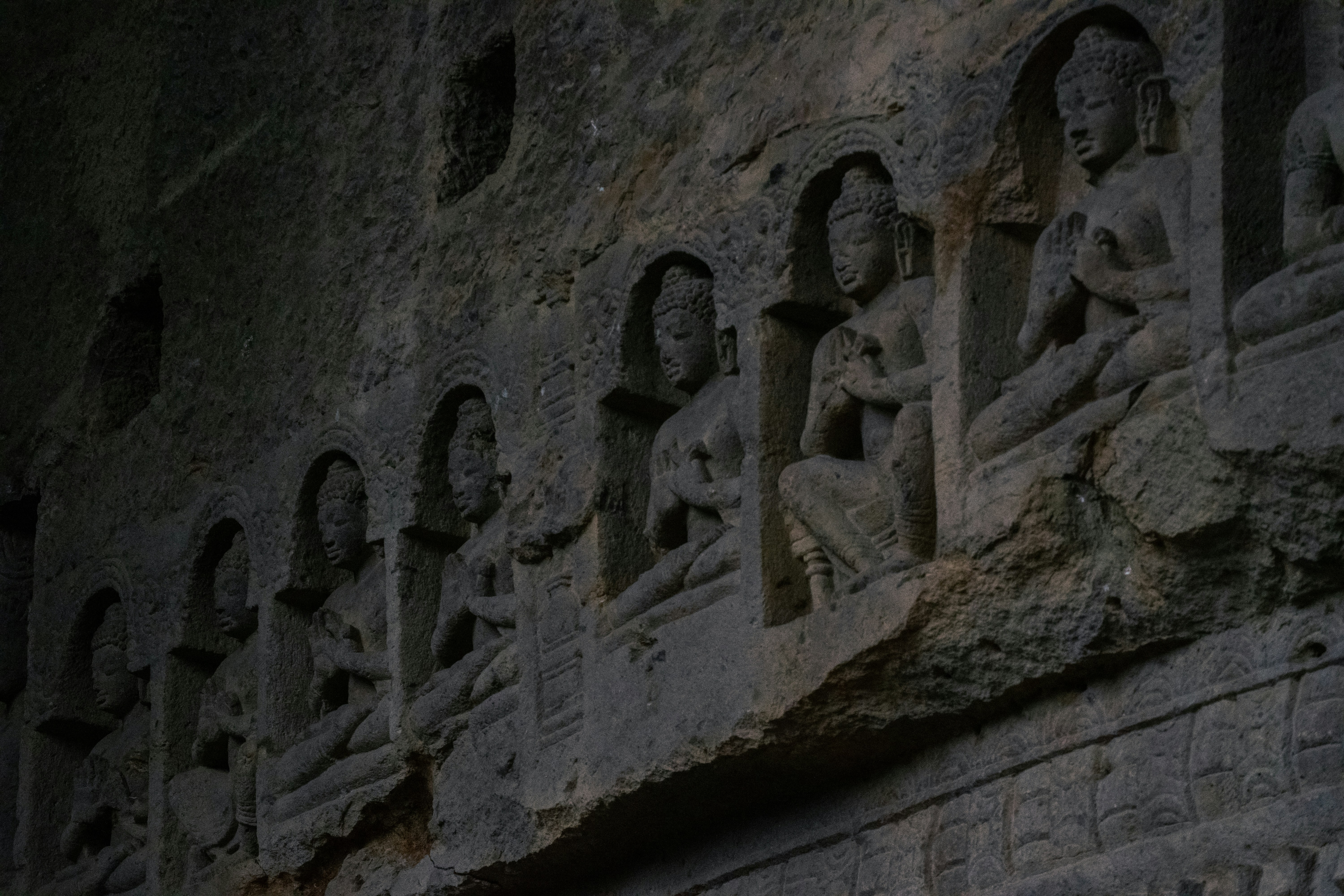 Row of Silent Guardians: Ancient Stone Relief in Dim Light