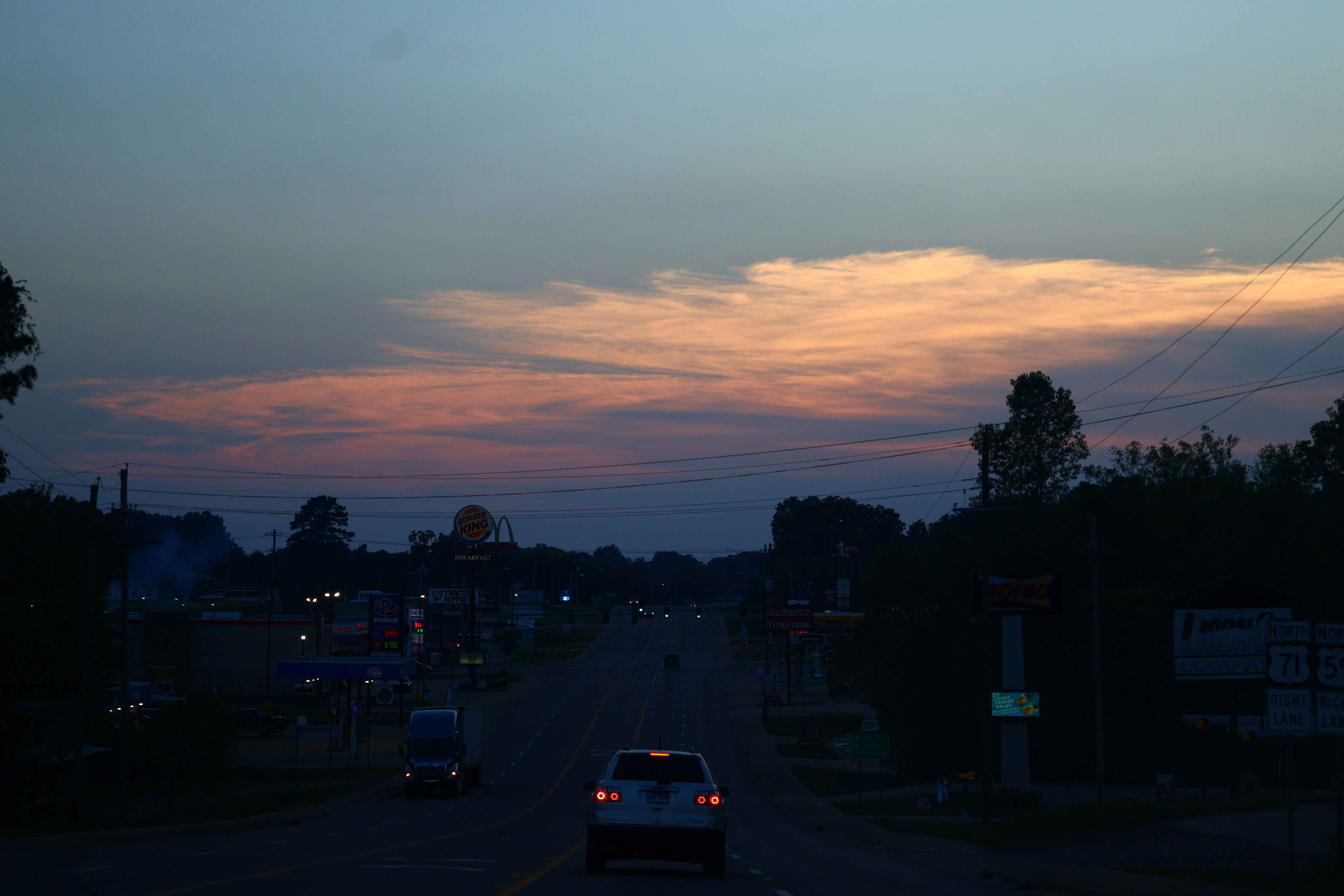 Sunset colors the sky over a road.