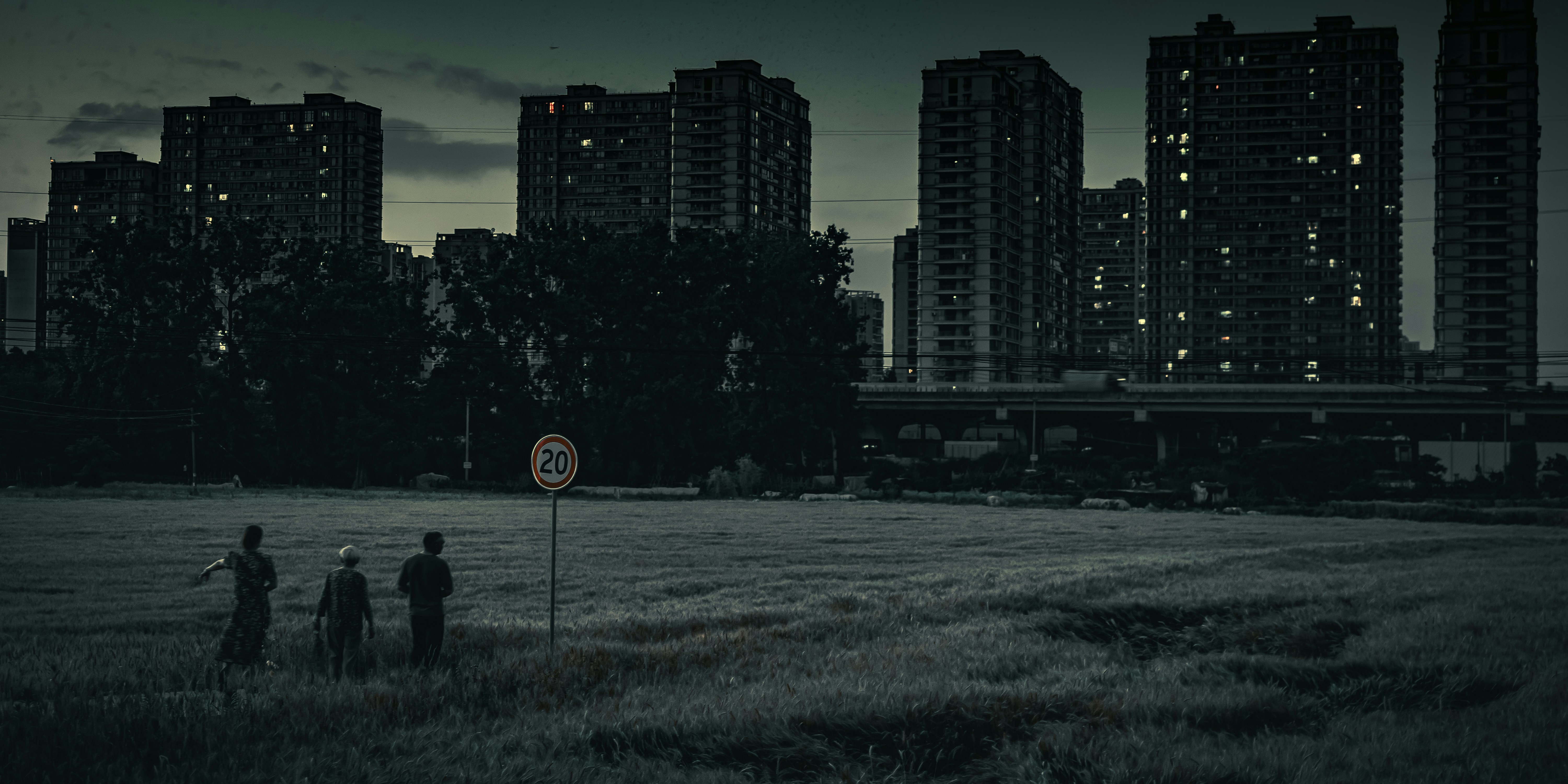 Three people walk toward city at dusk.