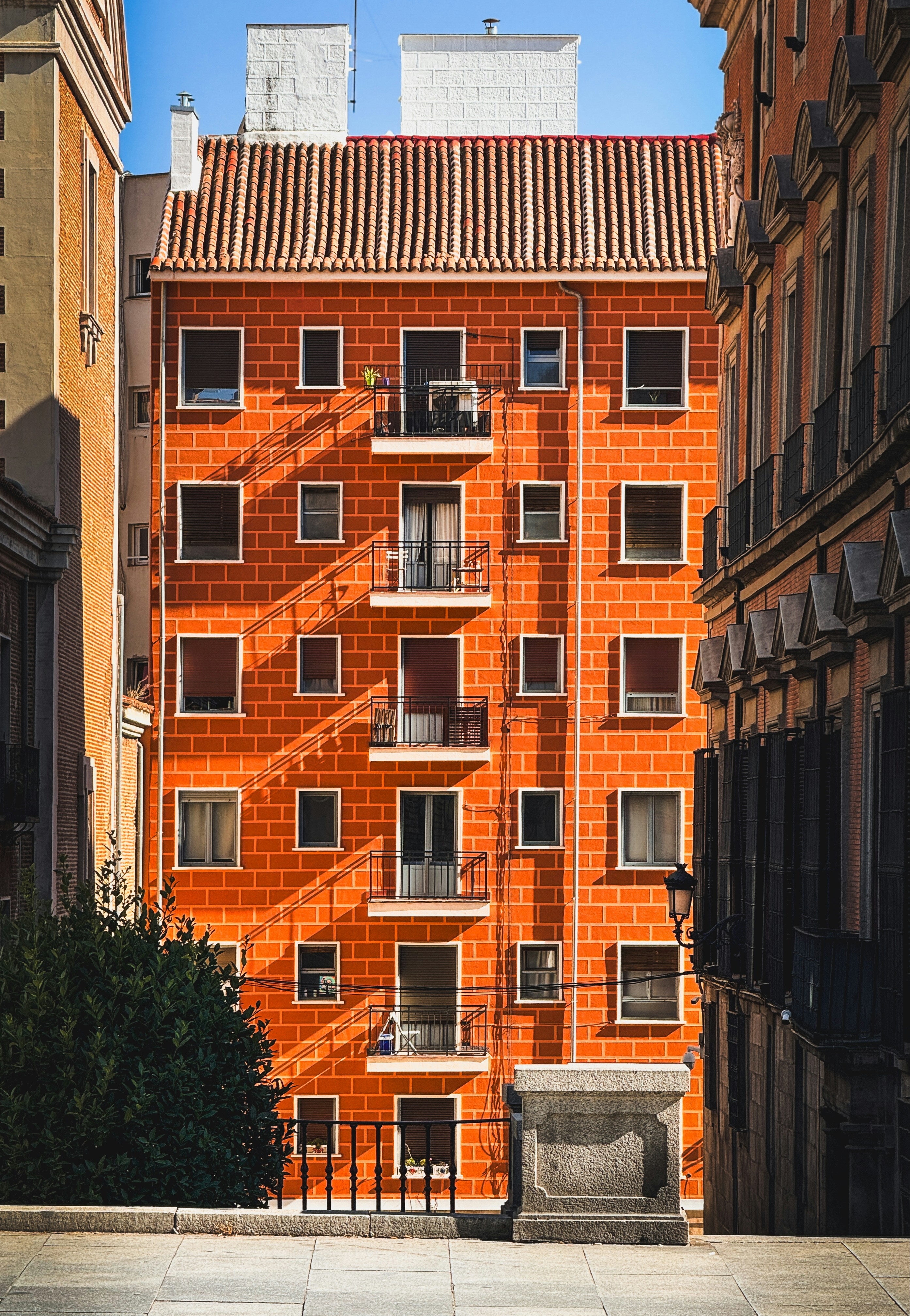 An orange brick building stands tall between other buildings.