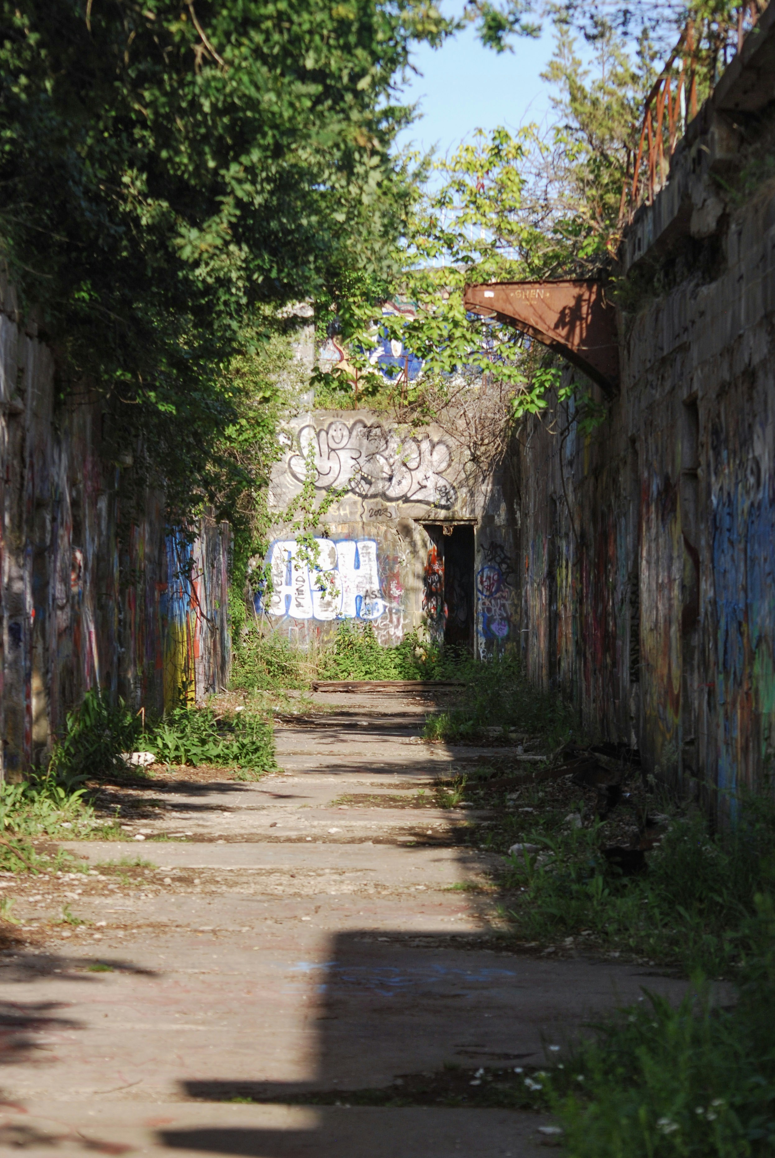courtyard with many different identical rooms at the eastern area of whetherill fort | A grungy concrete path leads through graffiti.