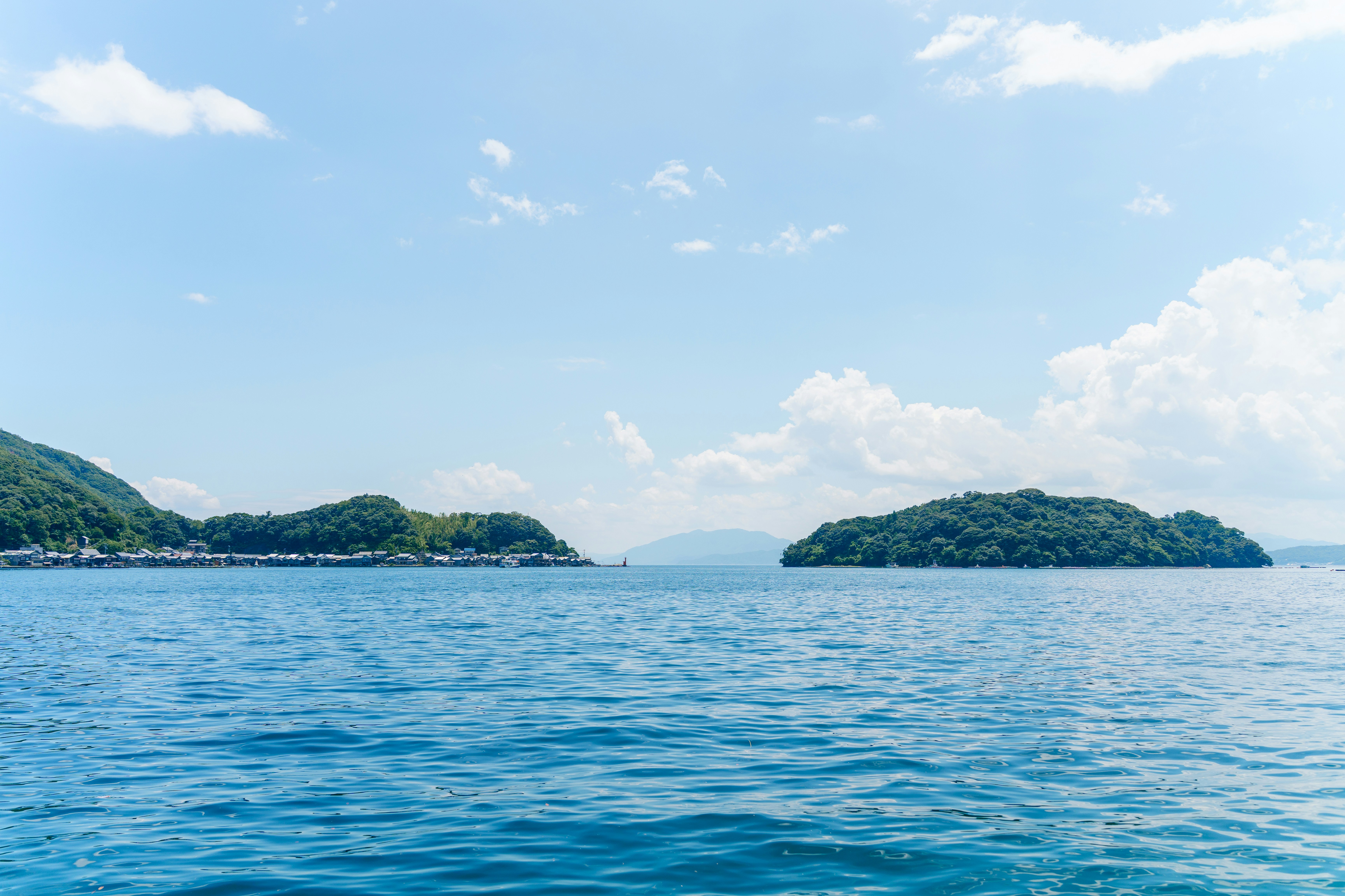 Islands sit in the blue ocean under a sunny sky.