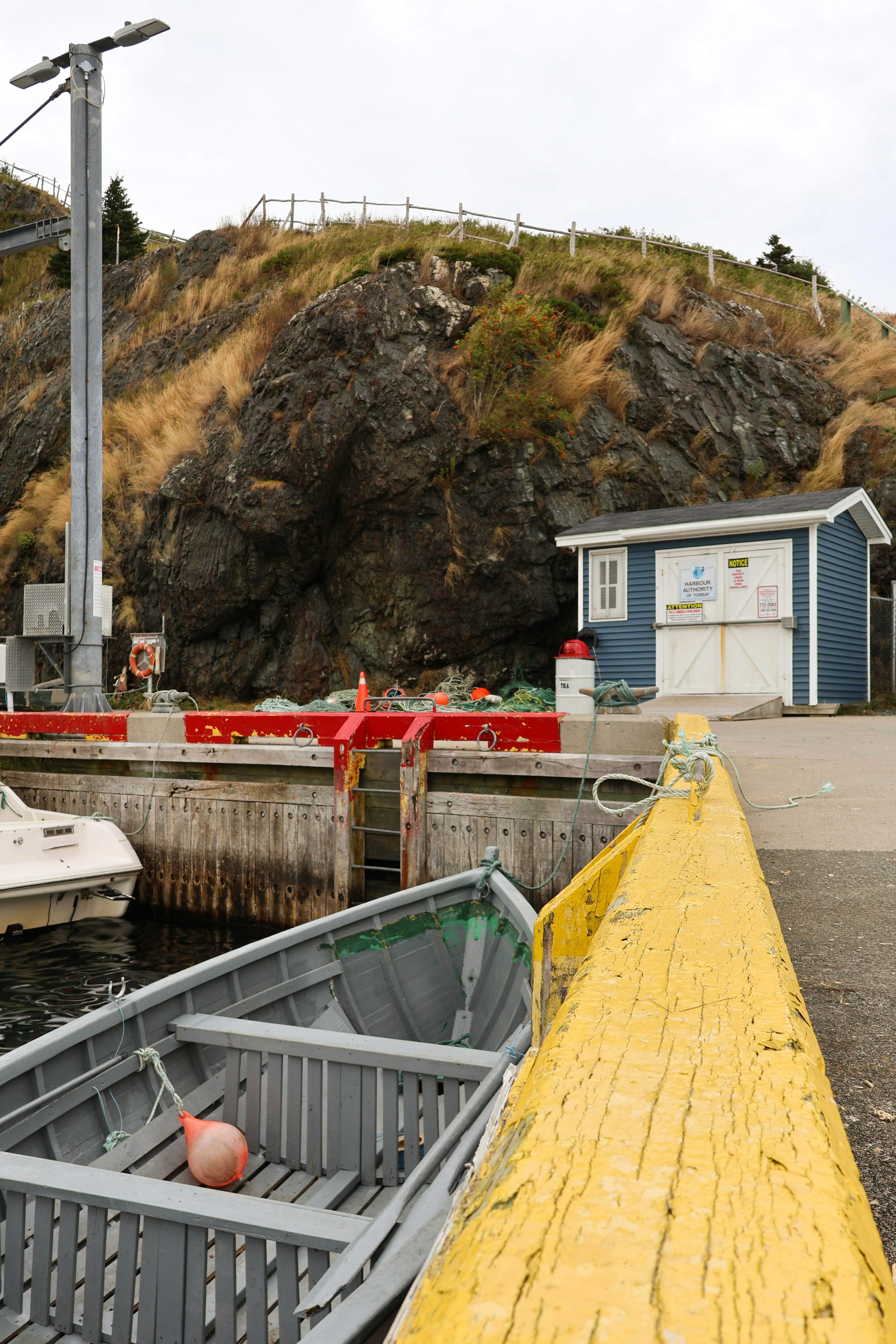 Fishing quay with small houses and rocks in Canada | A small boat sits at a quiet harbor.