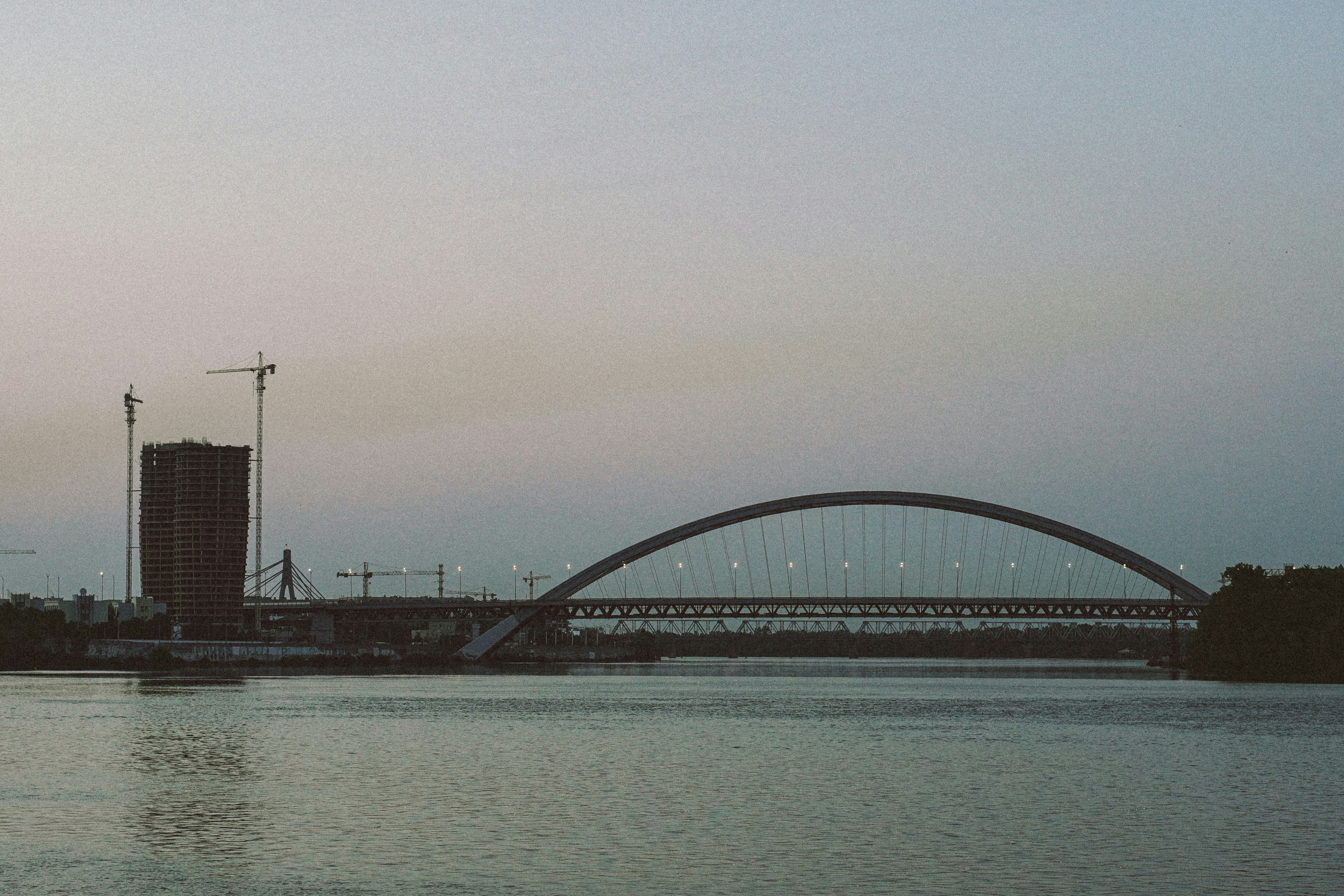 Bridge and buildings sit above calm water.