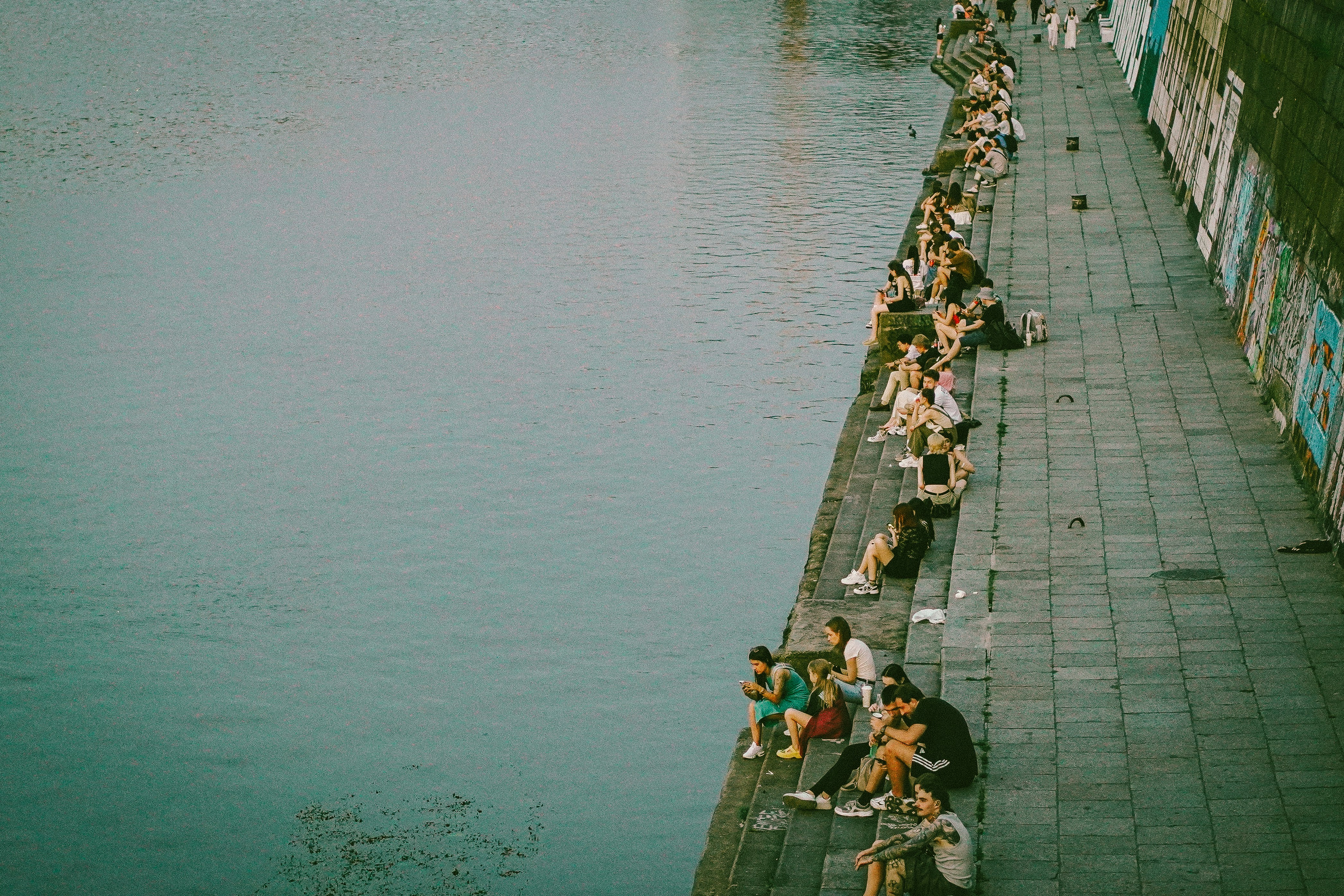 People are sitting on the edge of water.