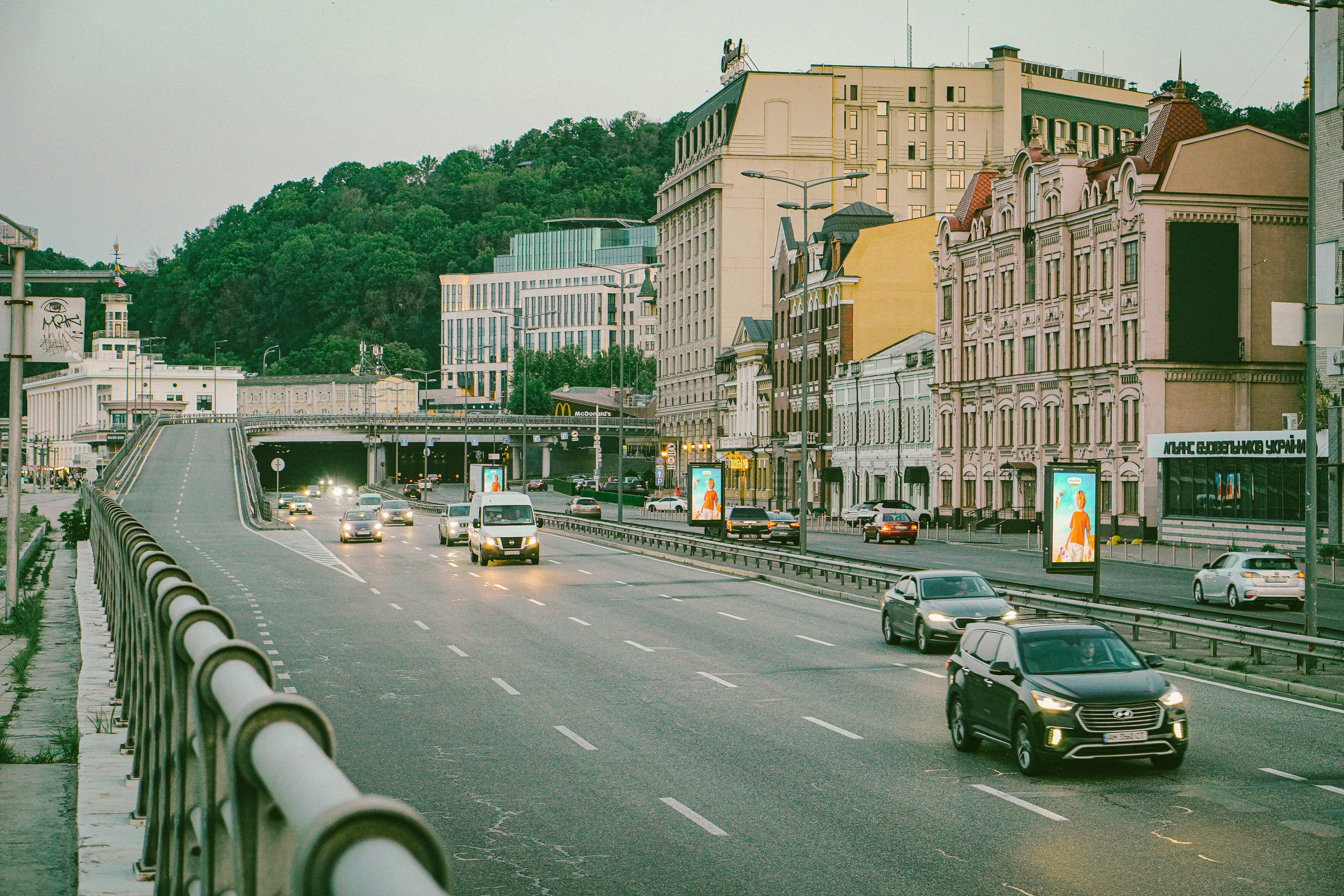Cars drive on a city road at dusk.