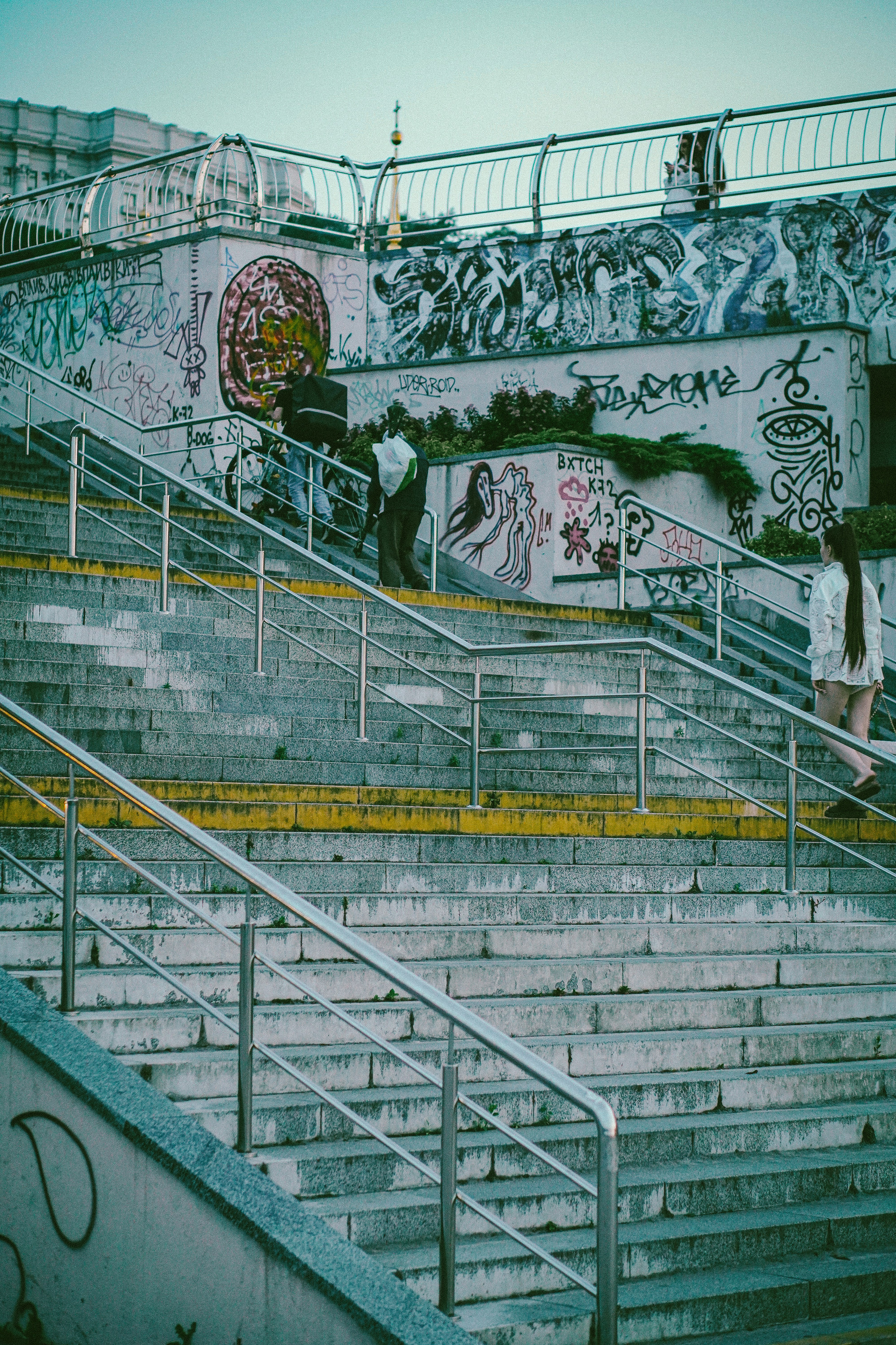People are walking up and down graffiti-covered stairs.