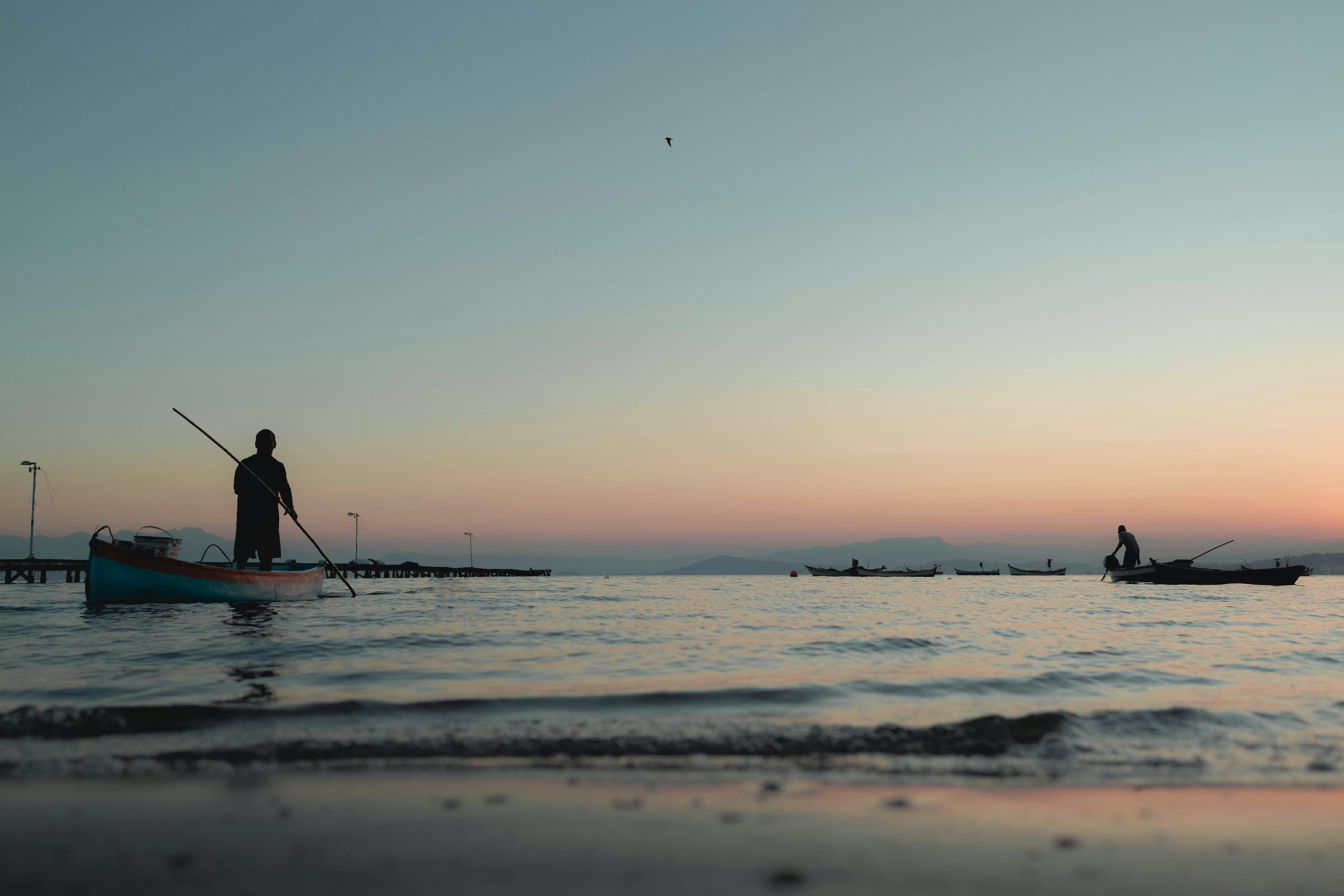 Calm beach in Brazil with fisherman | Fishermen on boats at sunset.