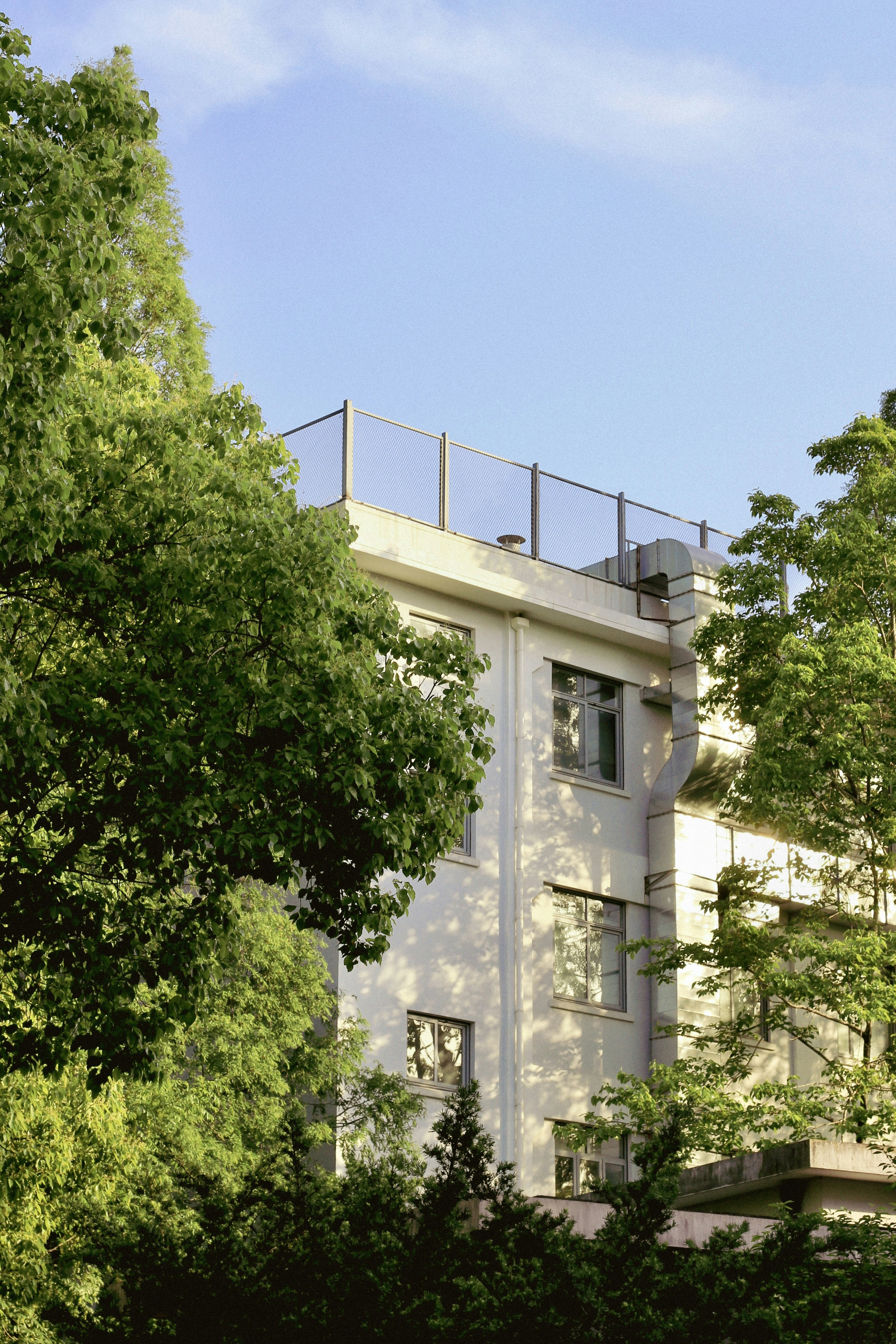 Building surrounded by trees under a blue sky.
