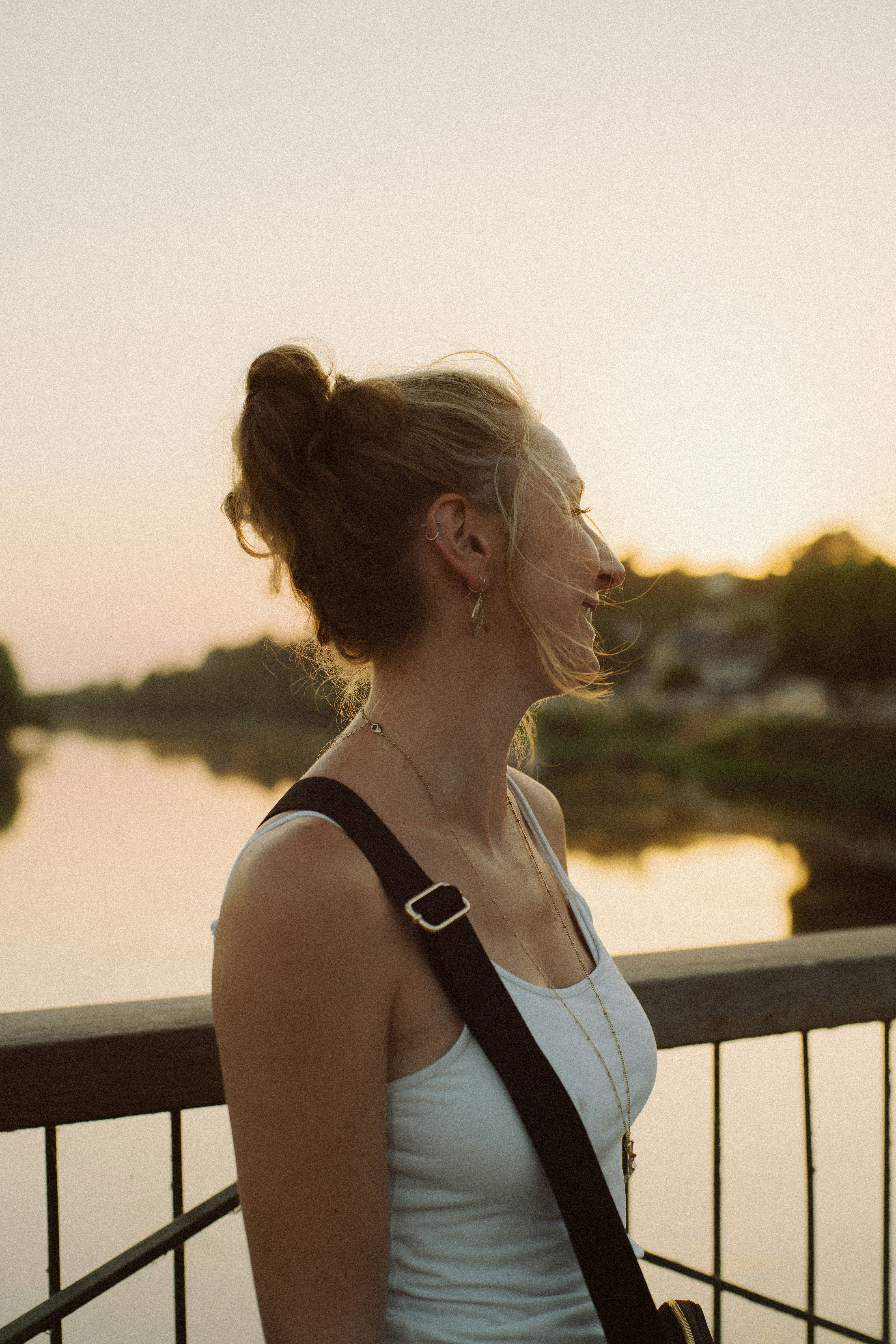 Woman smiles, enjoying the sunset by the river.